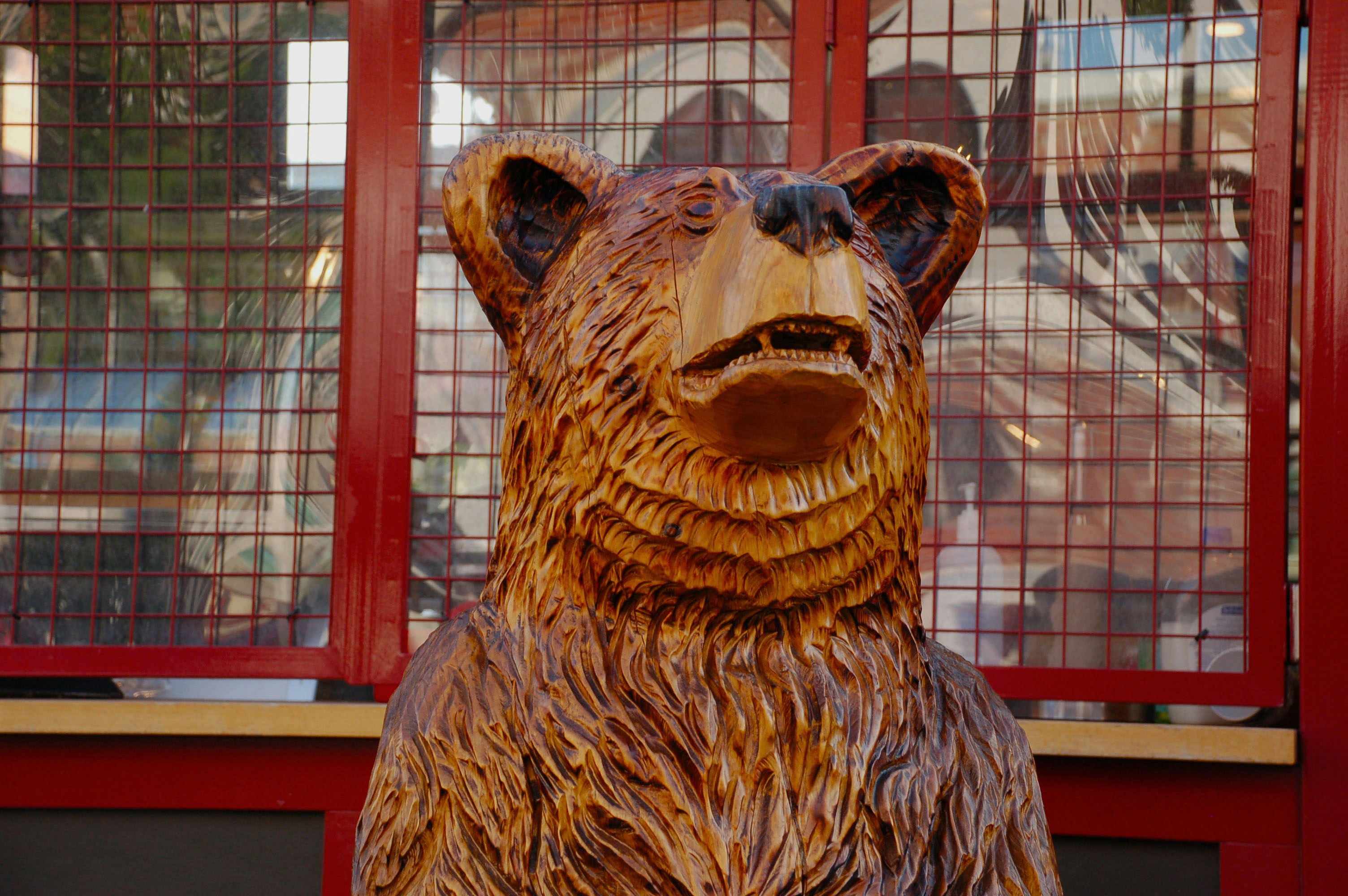 Intricately carved wooden bear sculpture standing proudly against a vibrant red backdrop.