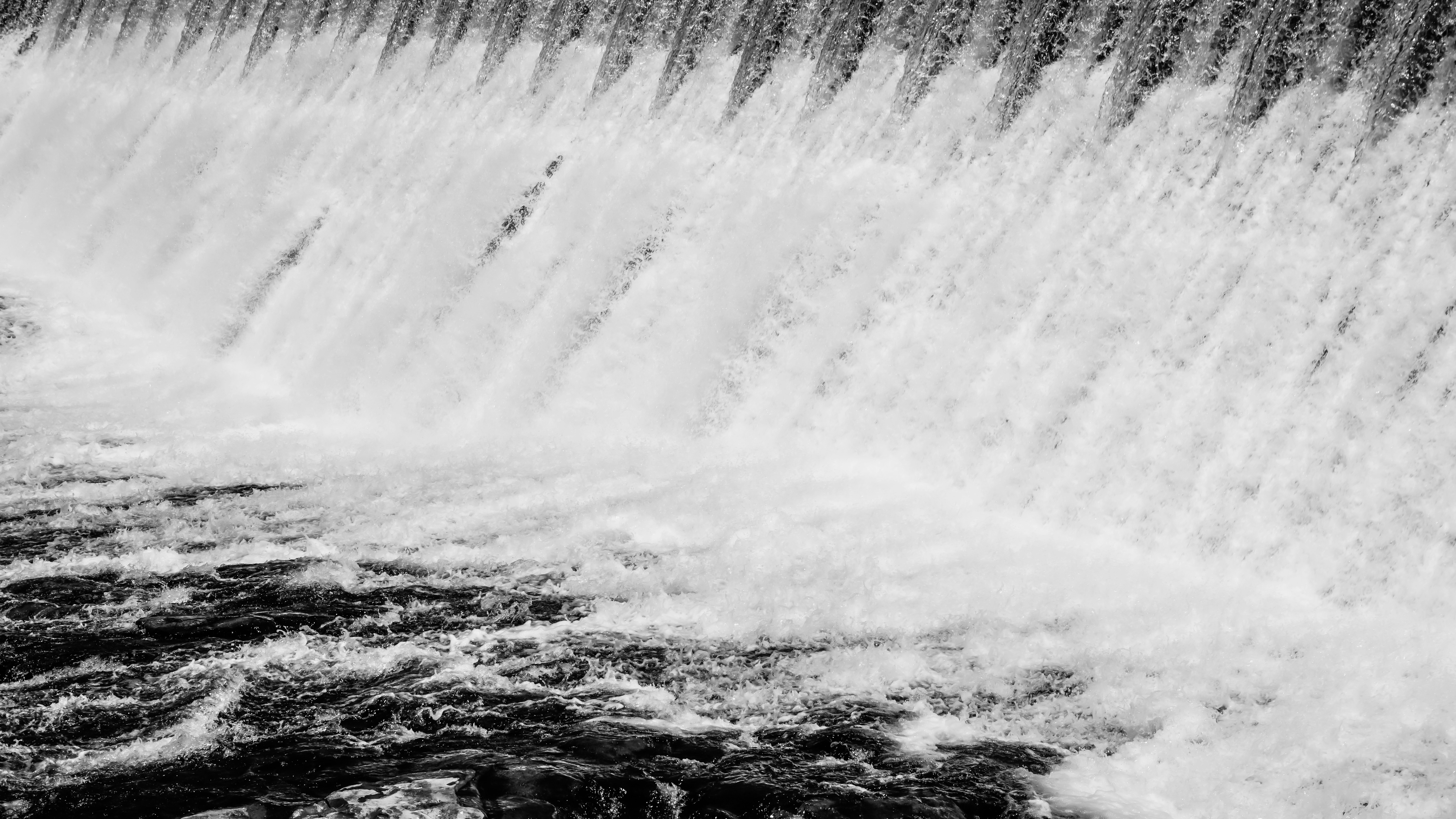 Monochrome image of a cascading waterfall with textured water flowing over a ledge.