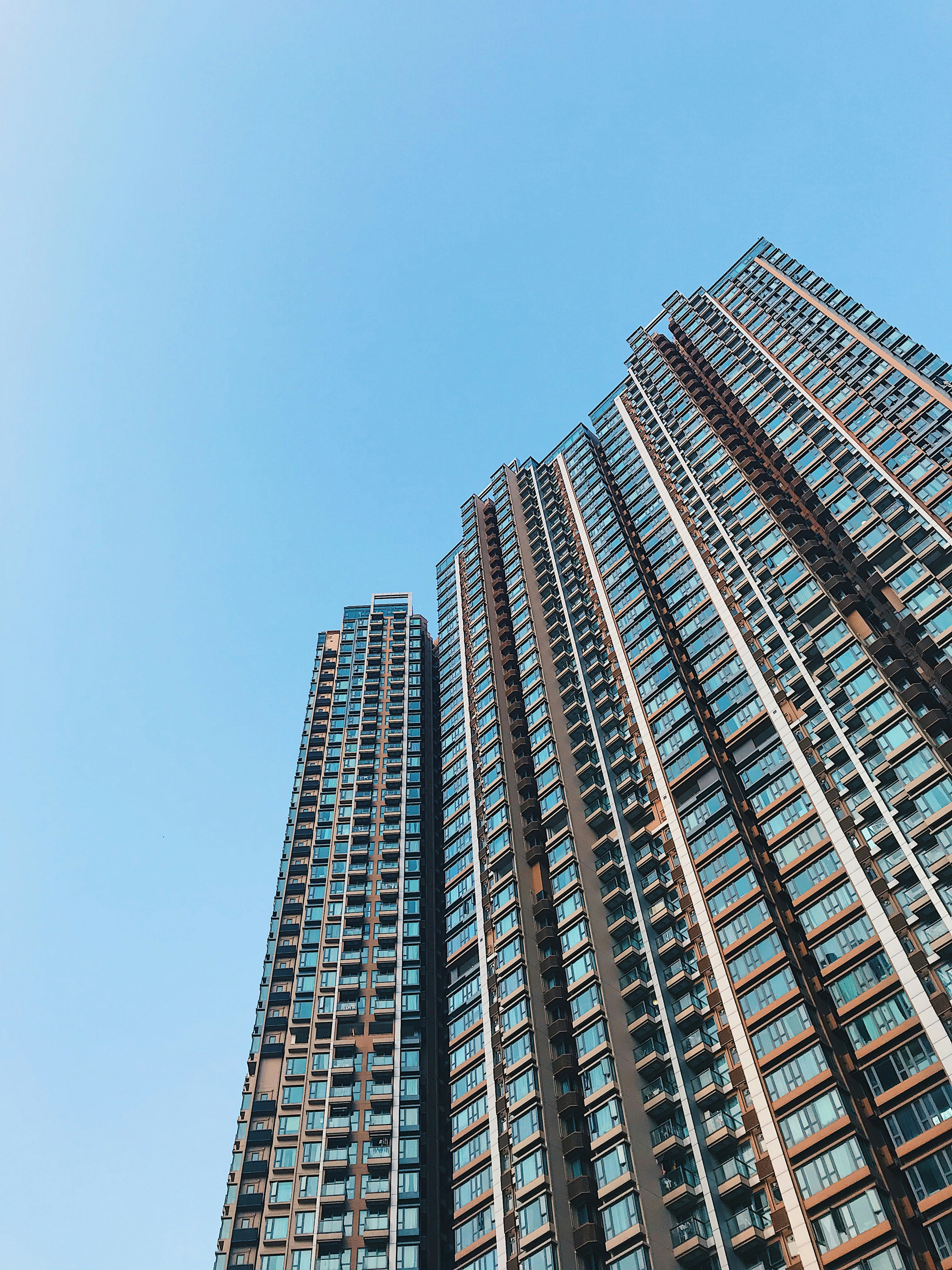 Tall residential skyscrapers rise against a clear blue sky, showcasing modern architecture and glass facades.
