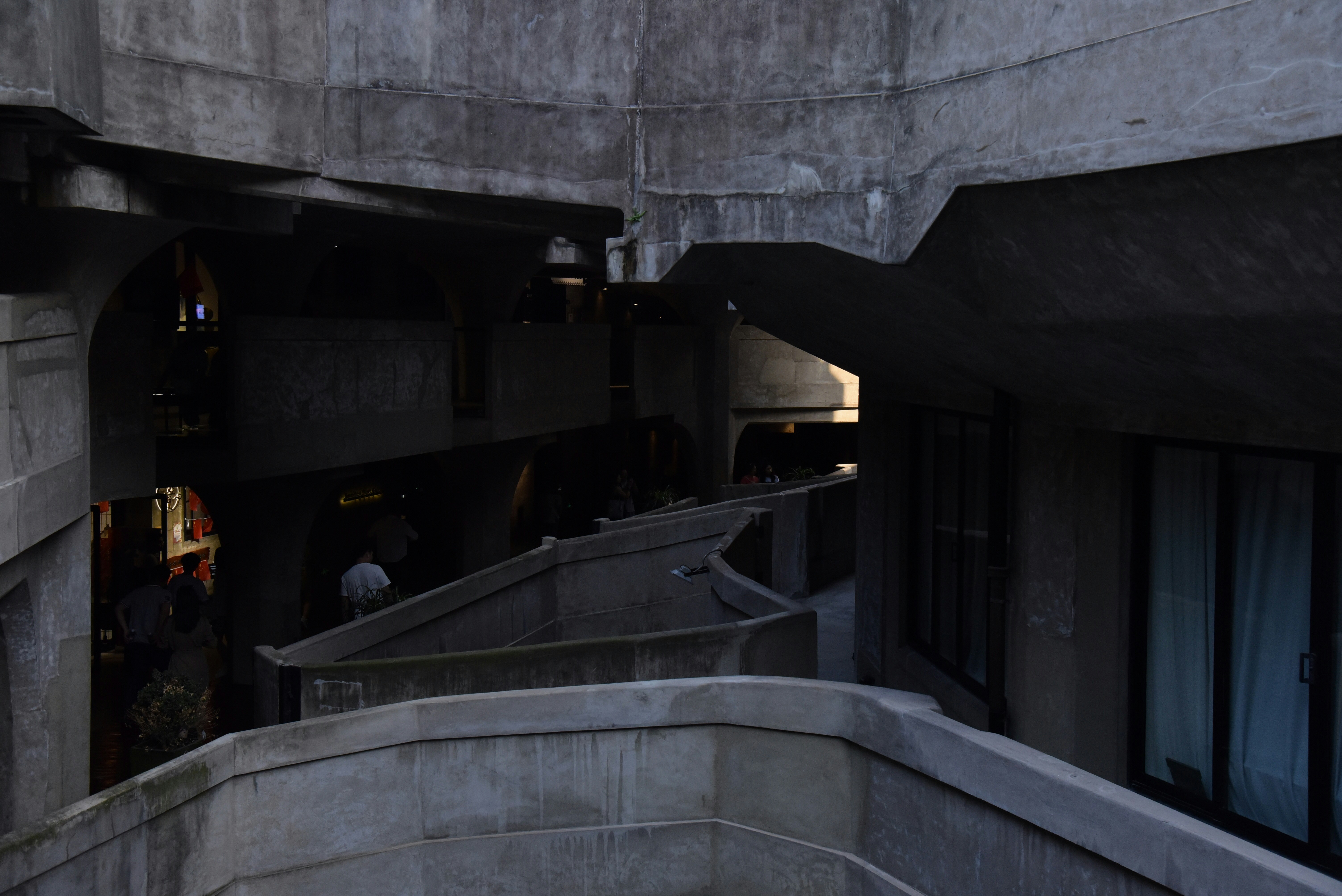 Intricate concrete architecture featuring winding pathways and soft ambient lighting, showcasing a blend of modern design and urban life.