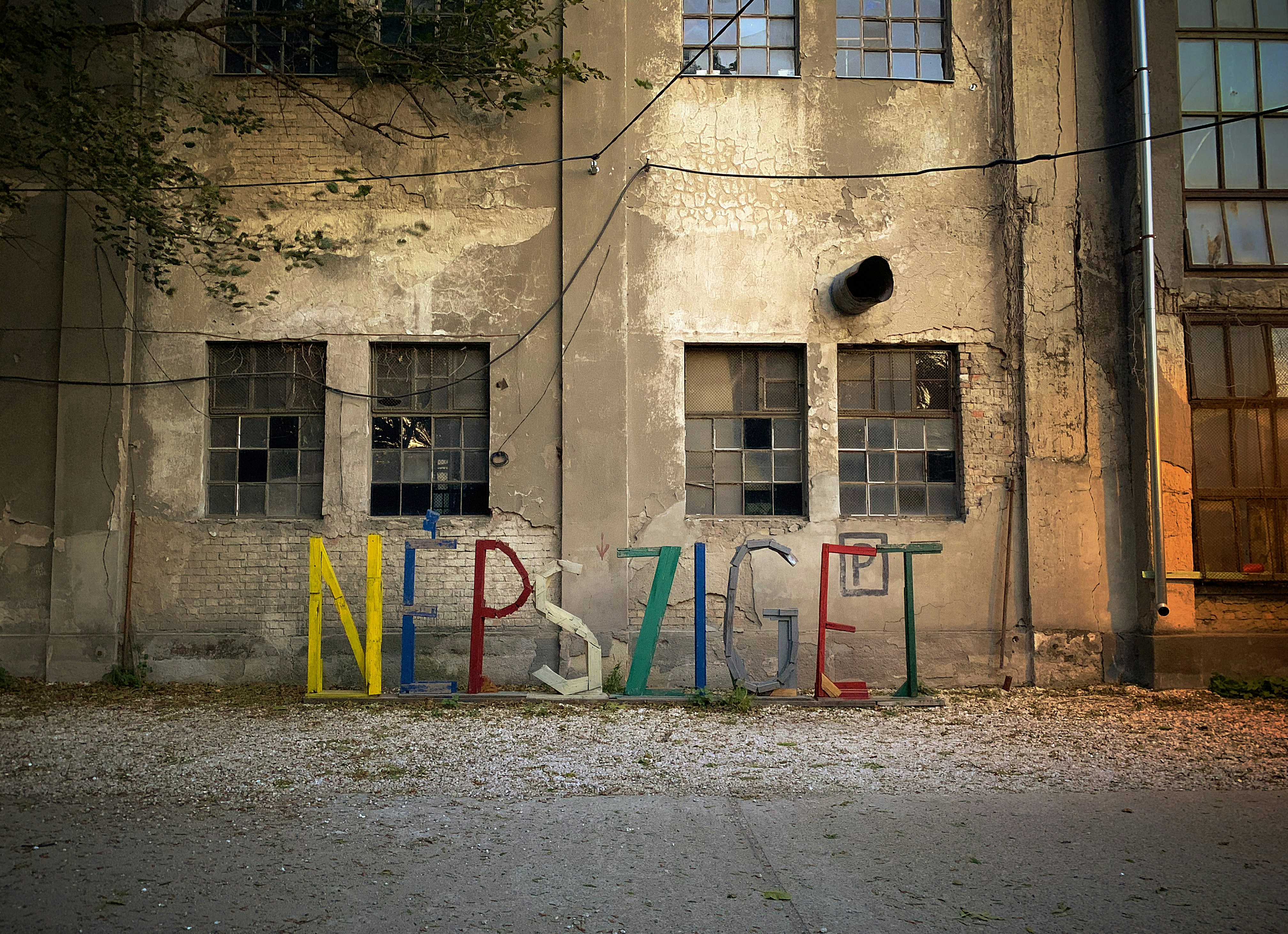 Vibrant letters spelling 'NEPSZIGET' stand against a weathered industrial backdrop, showcasing urban art's playful side.