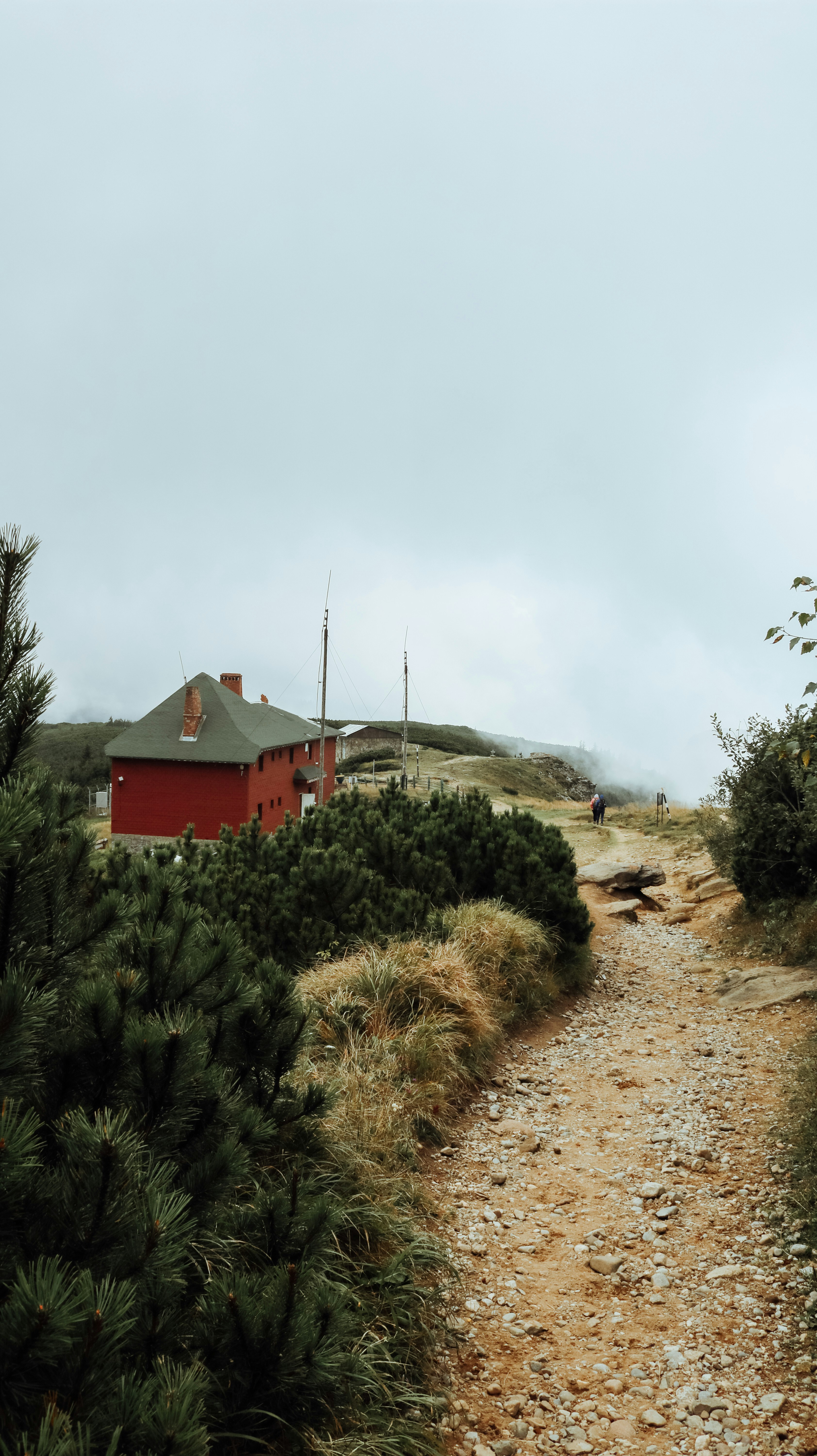 Red Chalet Along a Rugged Path Under Misty Skies