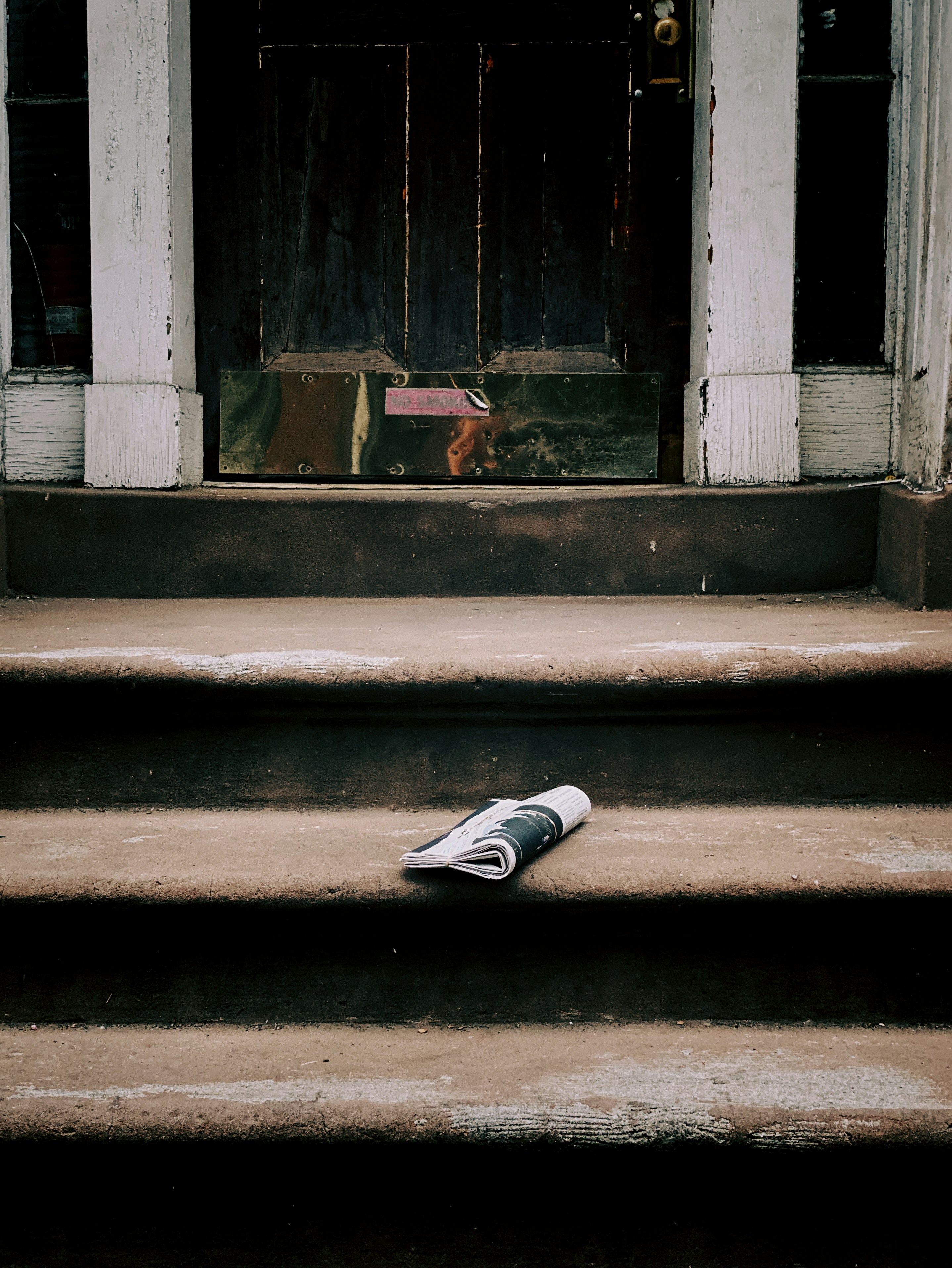Stillness on the Stoop: A Lone Newspaper Keeps Watch by the Door