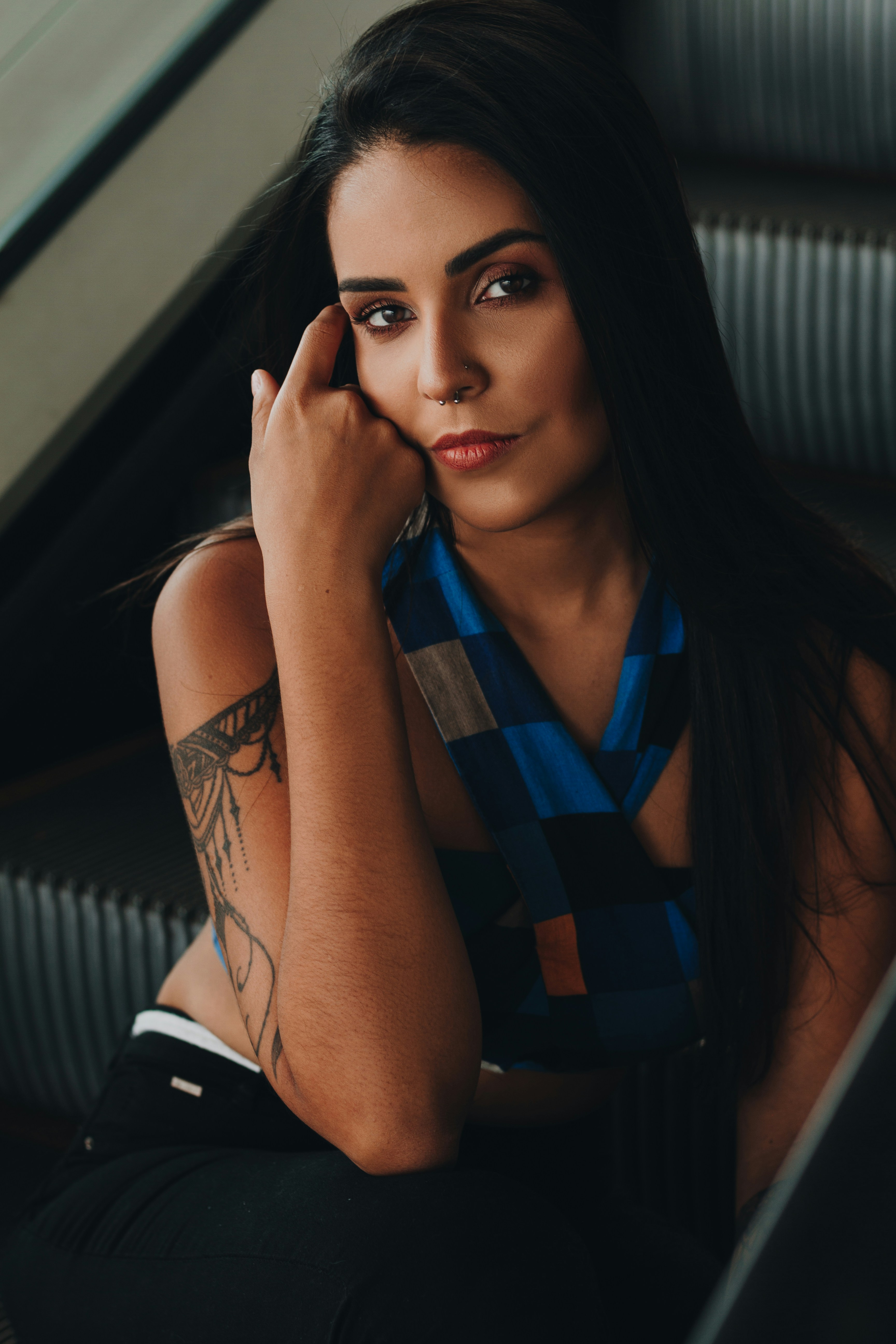 Woman wearing blue and black halterneck top sitting and touching her ...