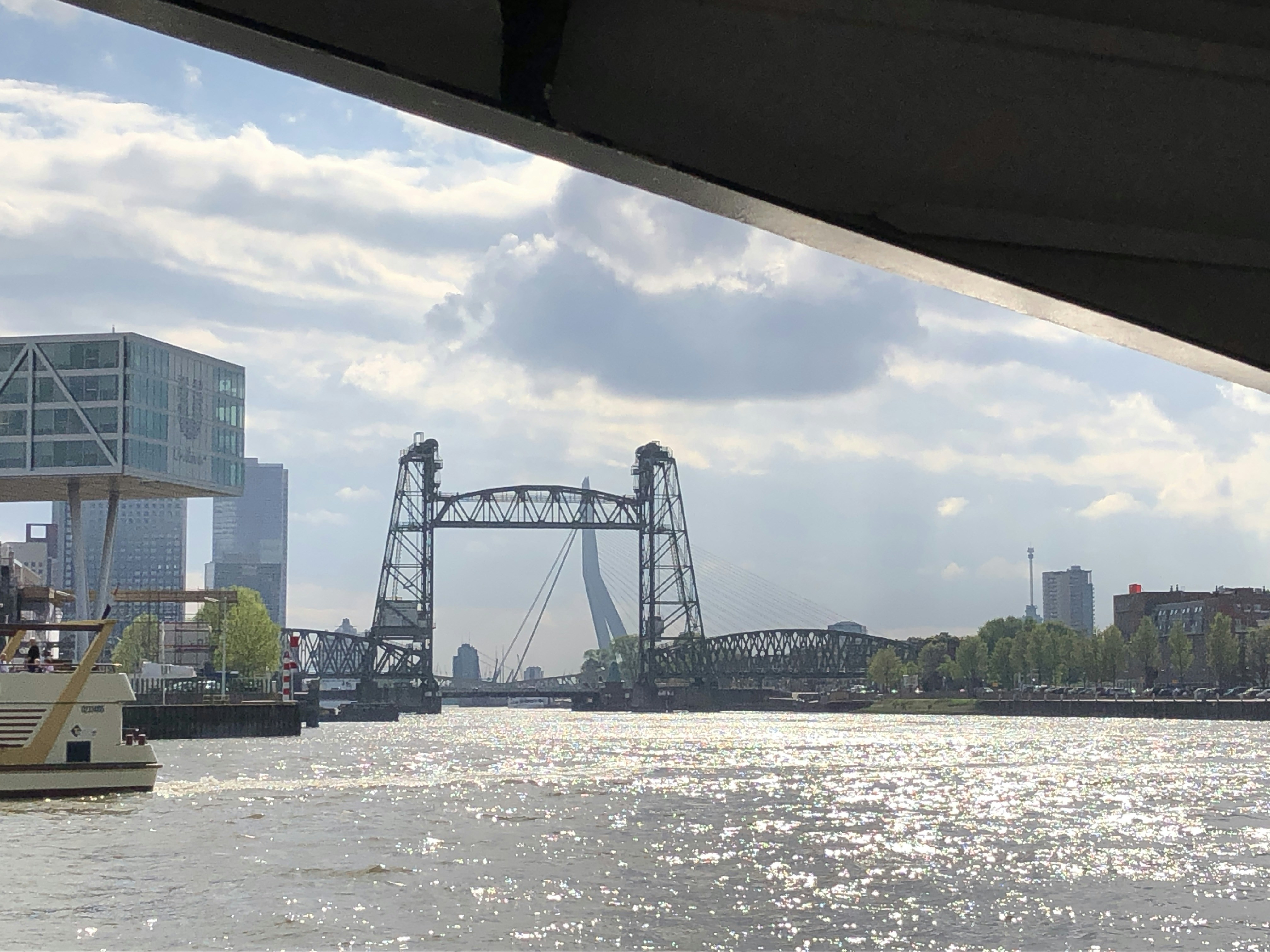 Historic iron bridge framed by clouds and modern architecture over a shimmering river.