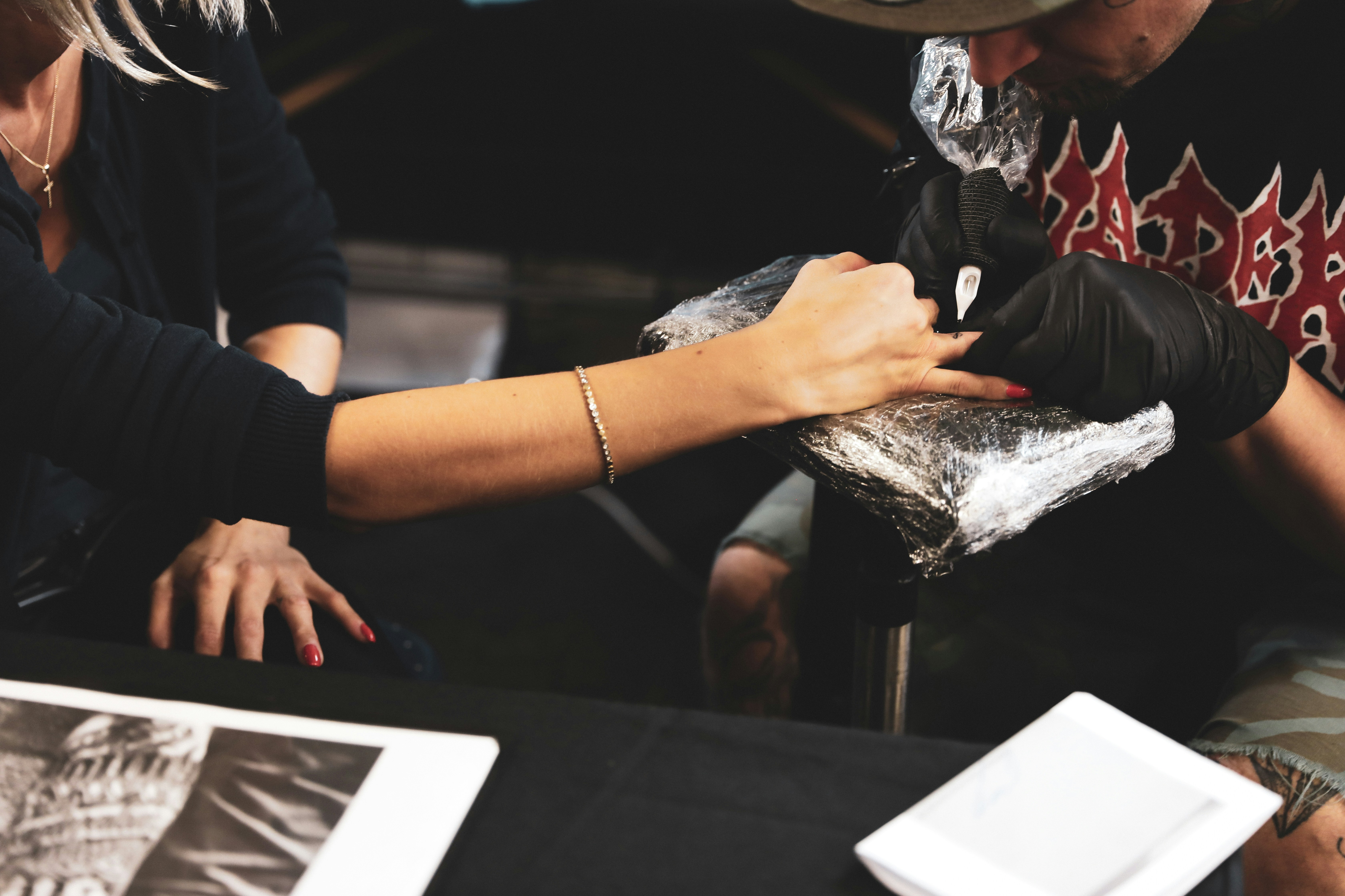 Tattoo artist meticulously applying ink to a client's hand, showcasing the intricate process of body art.