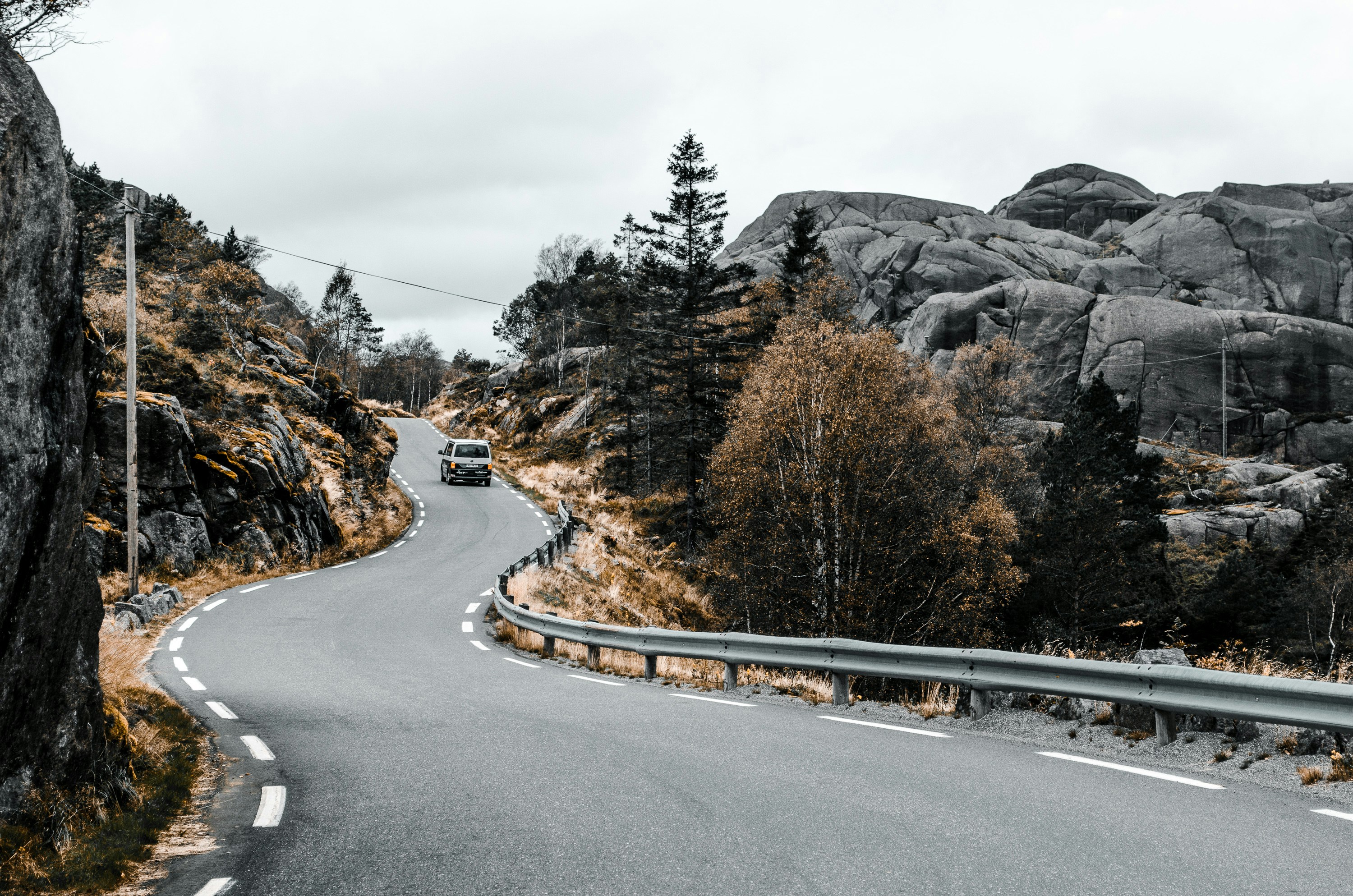 Autumn Bend on Granite Ridge: A Lone Car Navigates a Mountain Curve