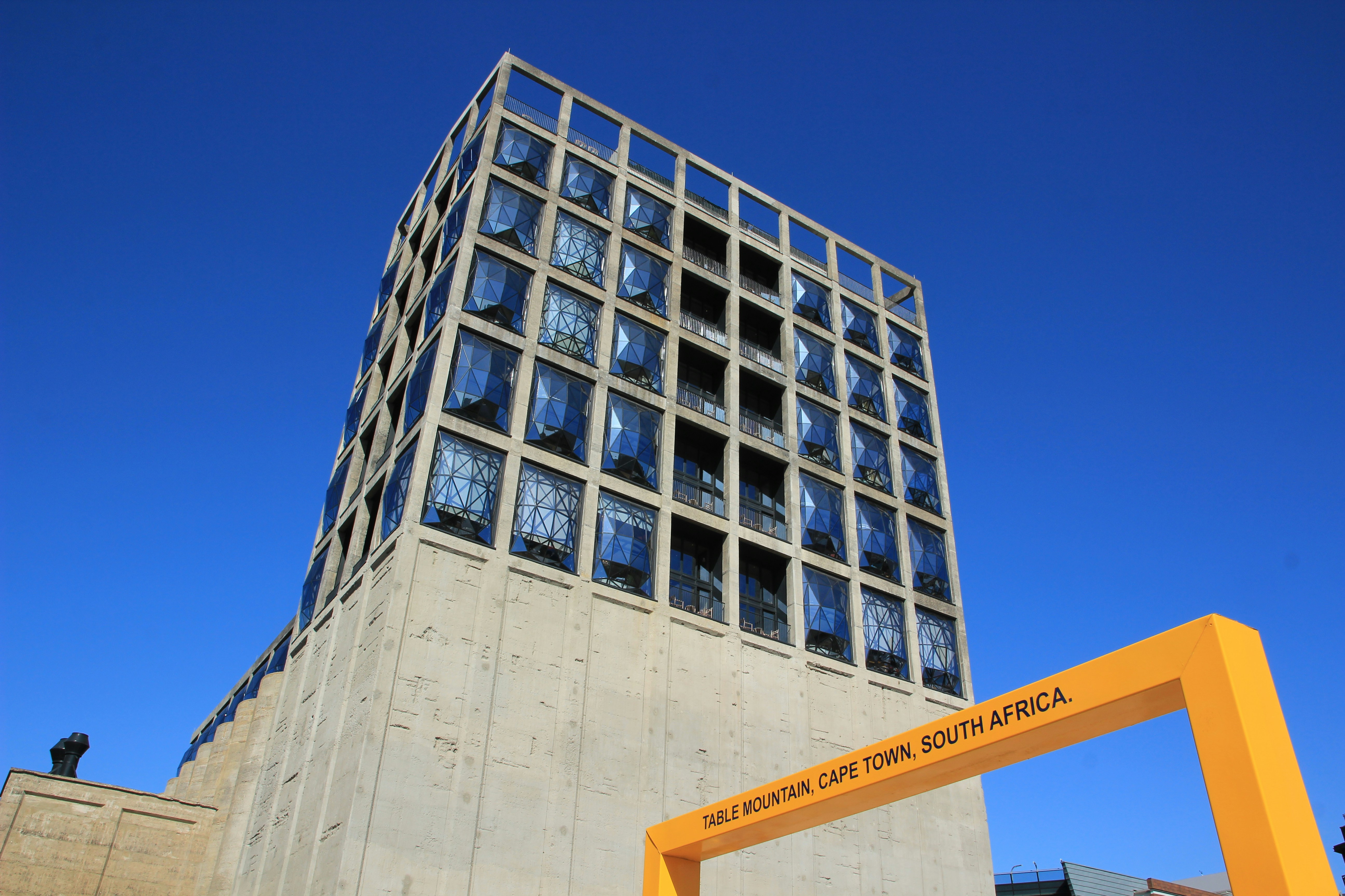 Modern concrete structure with grid-like windows under a vibrant blue sky.