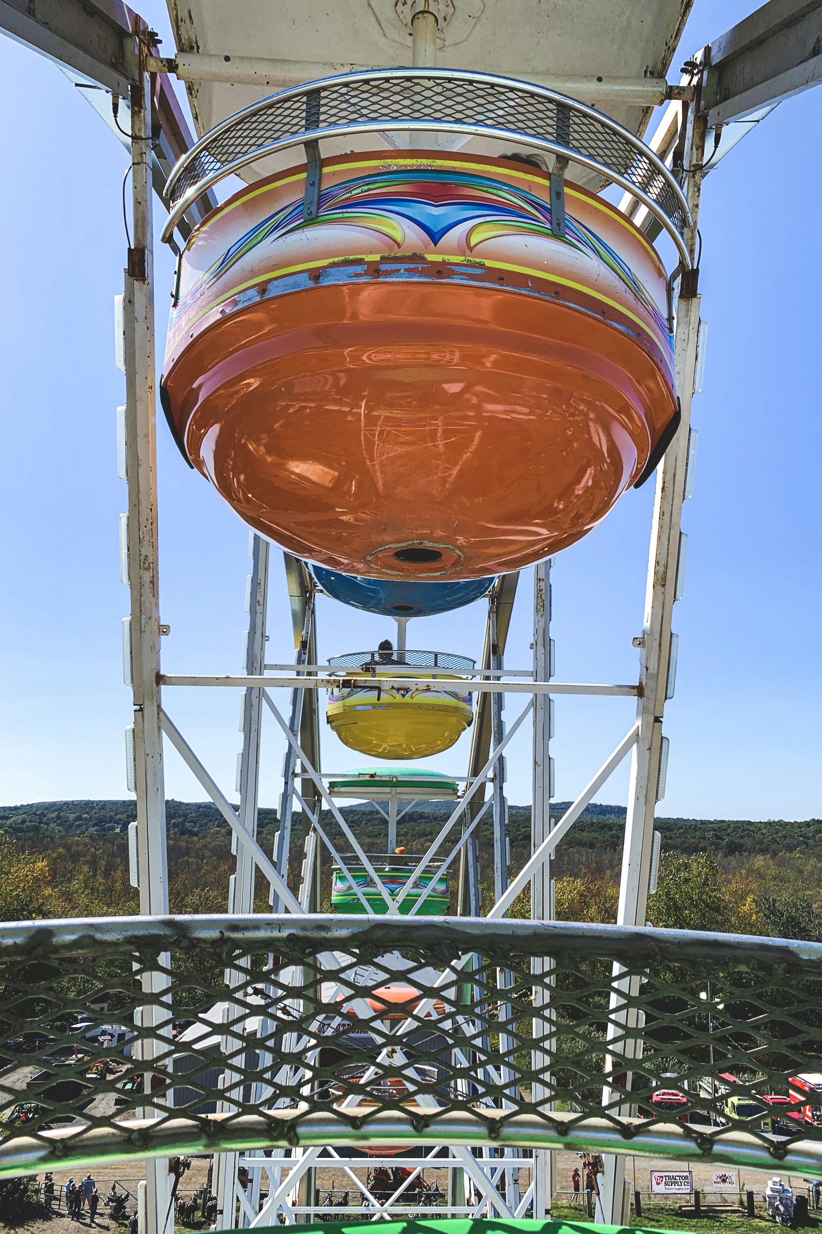Vibrant gondolas of a Ferris wheel viewed from below, showcasing their playful colors against a clear blue sky.