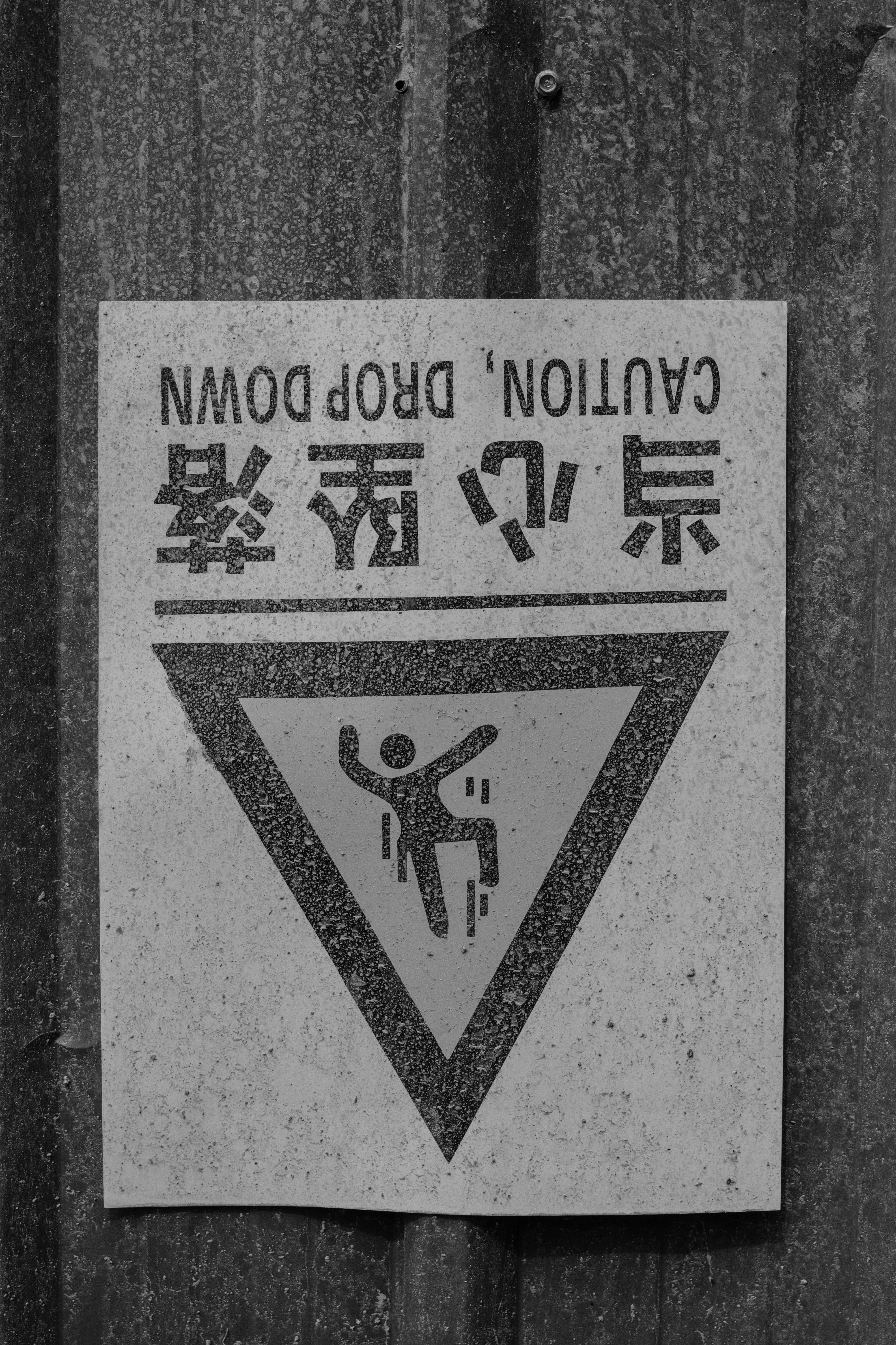 Upside-Down Caution Sign on a Weathered Metal Wall
