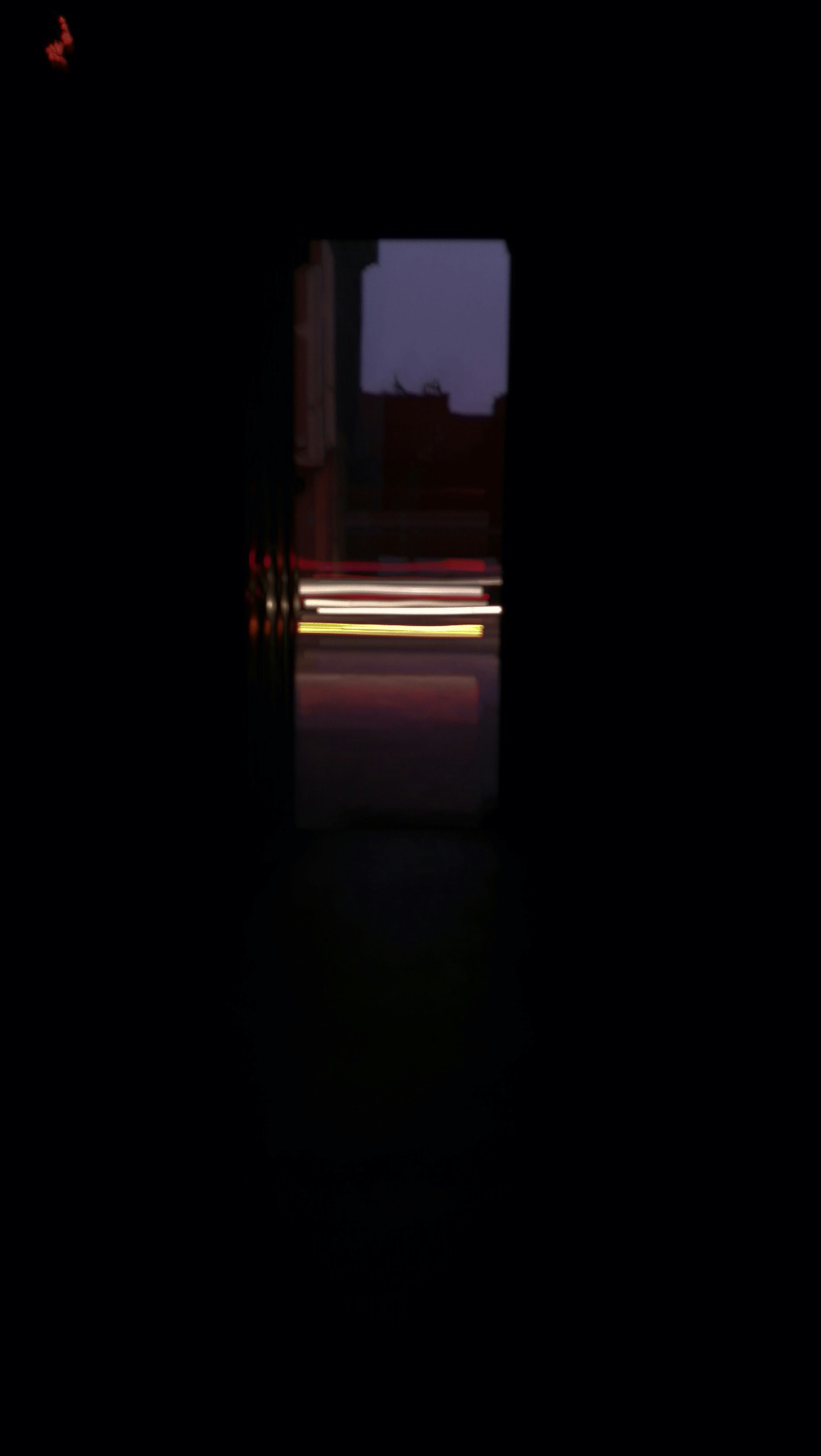 A dimly lit corridor capturing streaks of light from an opening, suggesting movement and depth. The contrasting darkness enhances the sense of mystery.
