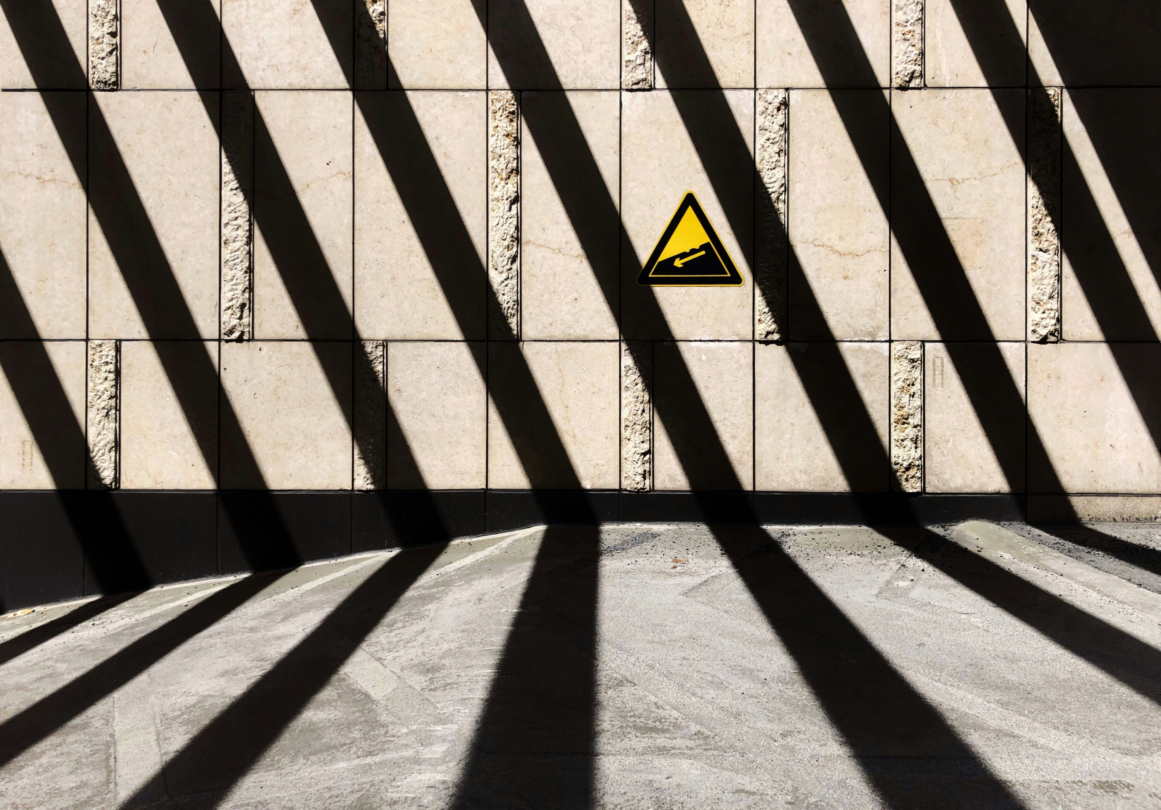 Crisscrossed Light: A Minimal Wall with a Yellow Warning Sign
