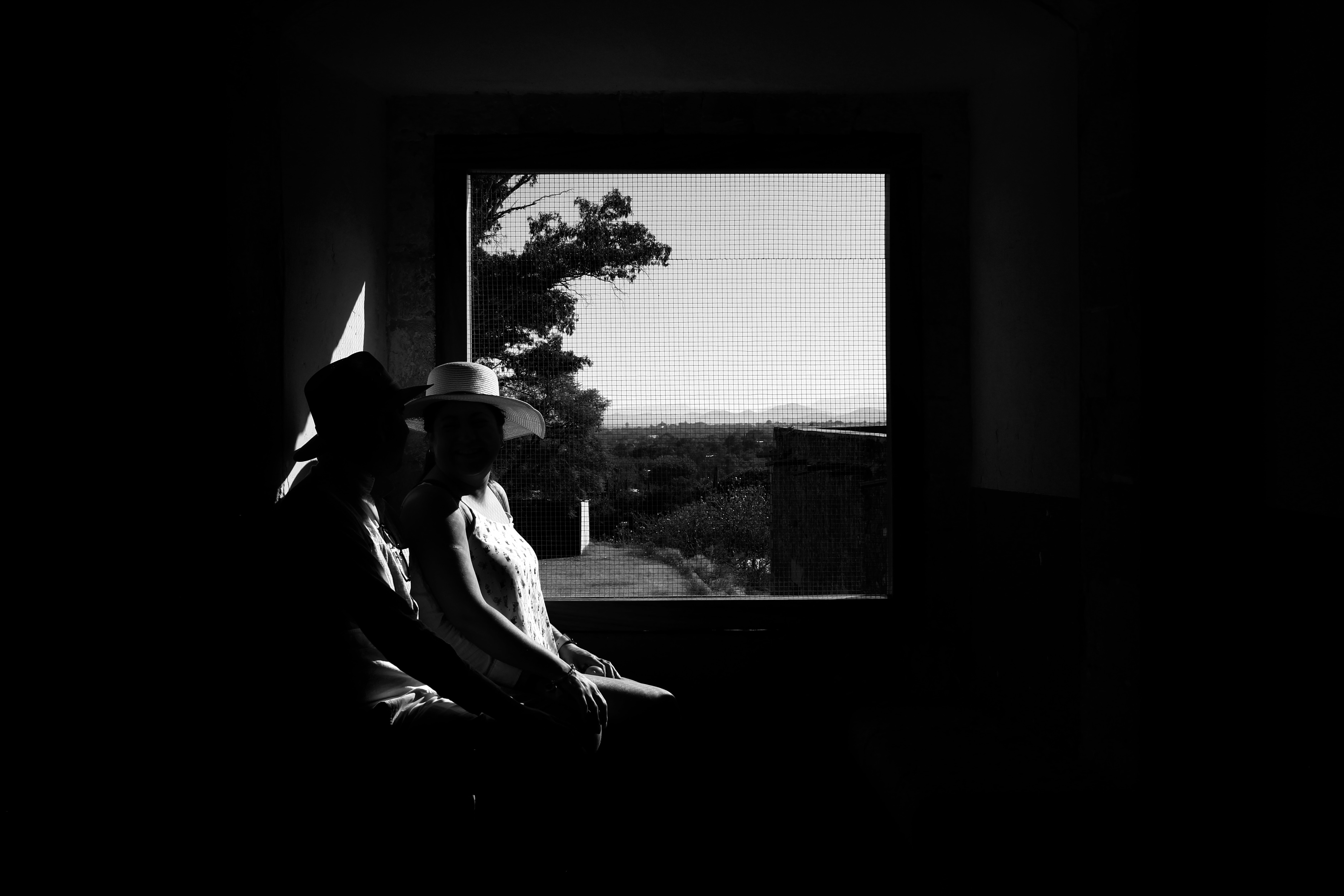 Silhouetted couple sitting by a window with a distant landscape view.