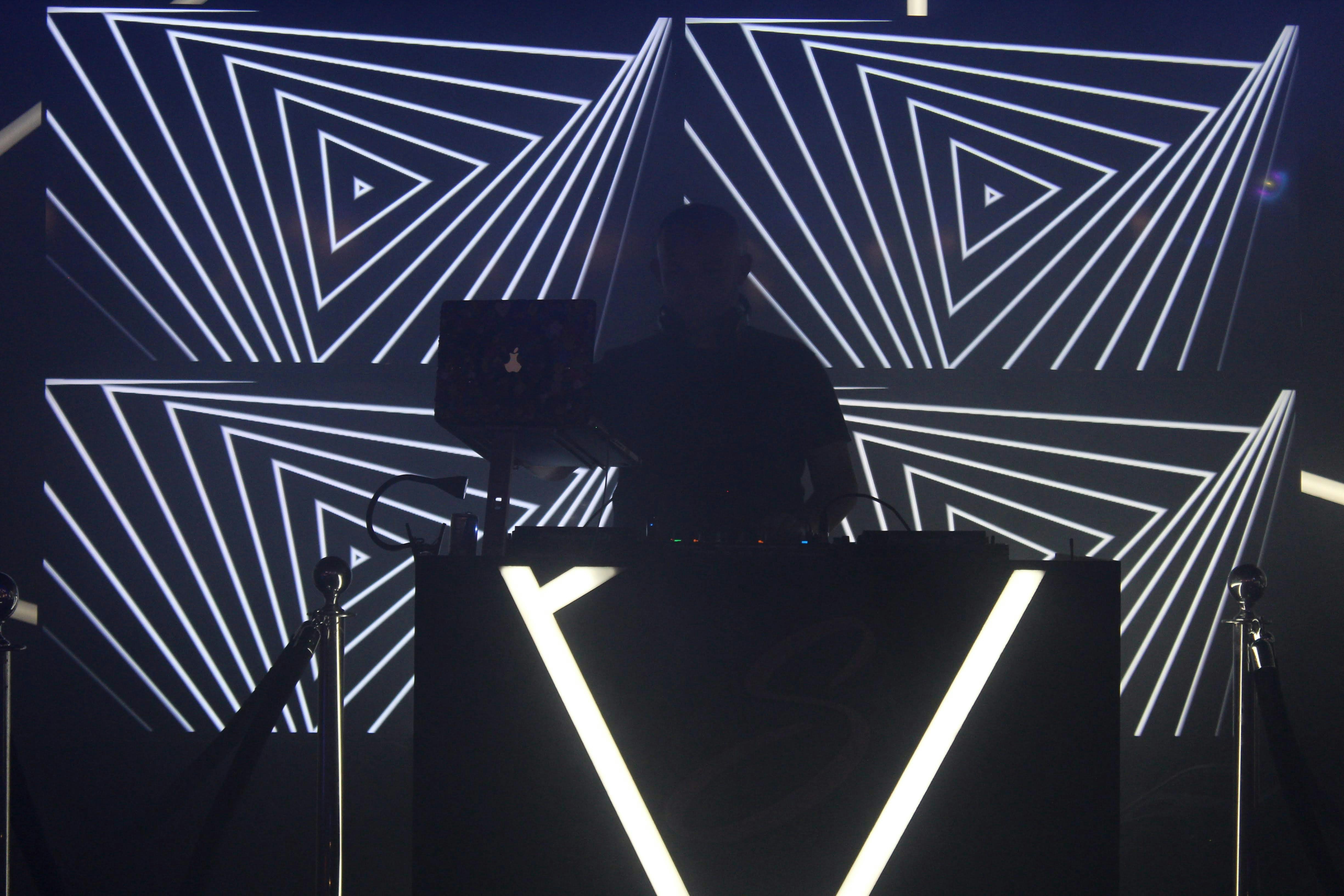 Center Stage Under a Neon Triangle Curtain: DJ Set Amid Geometric Light