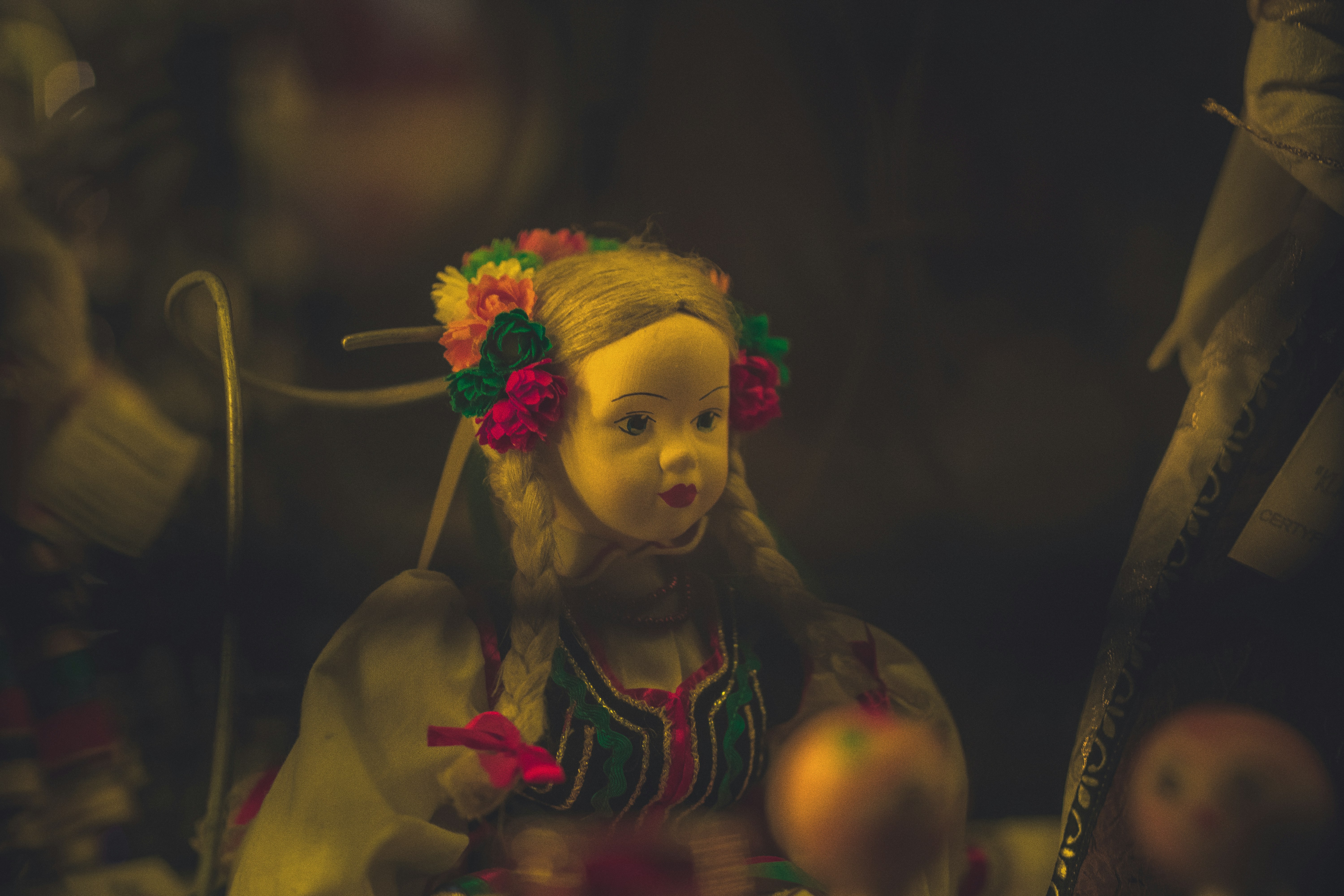 A vintage doll adorned with colorful flowers, exuding a sense of nostalgia and charm. The soft lighting enhances its delicate features.