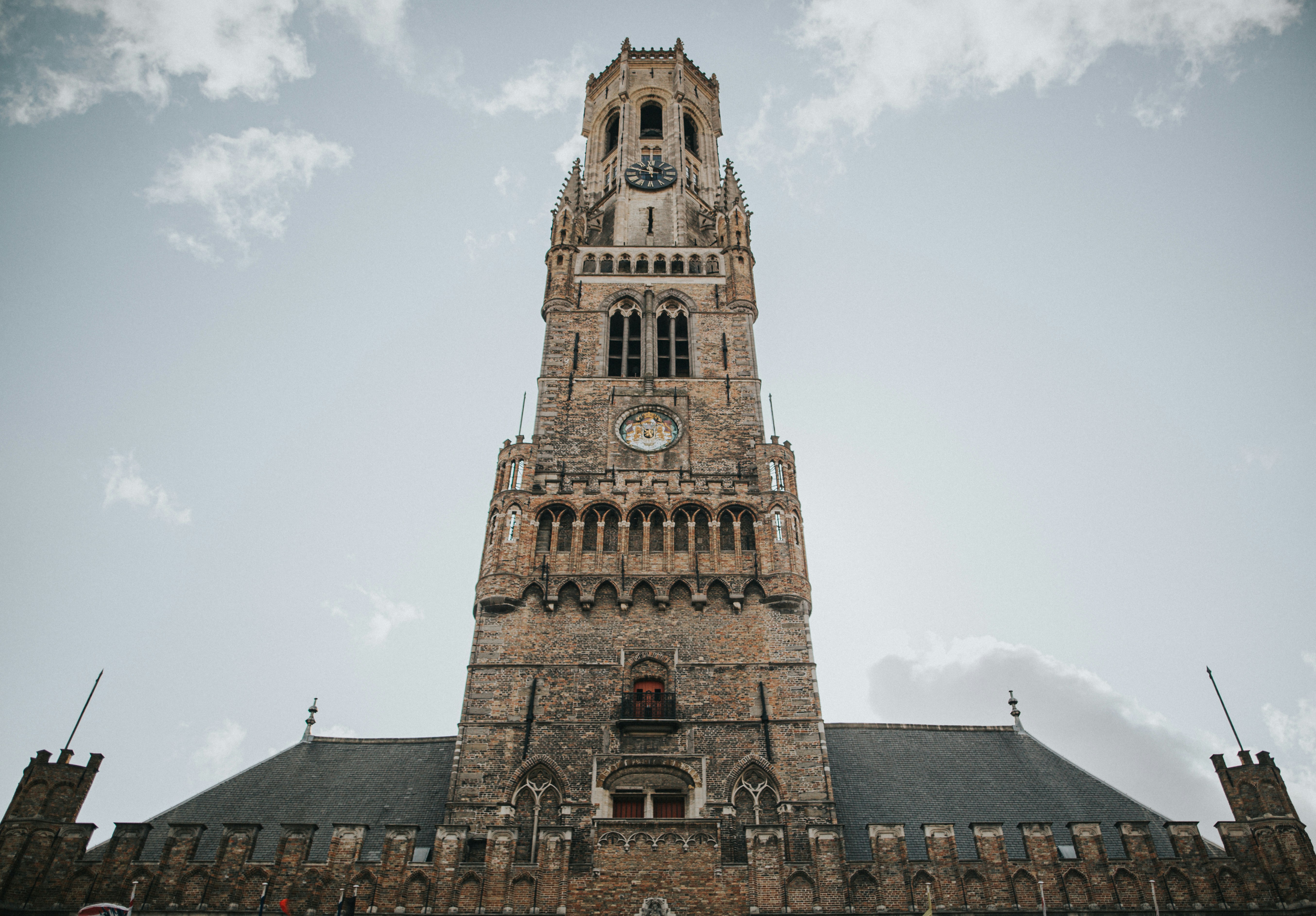 Towering stone church spire viewed from below against a cloudy sky.