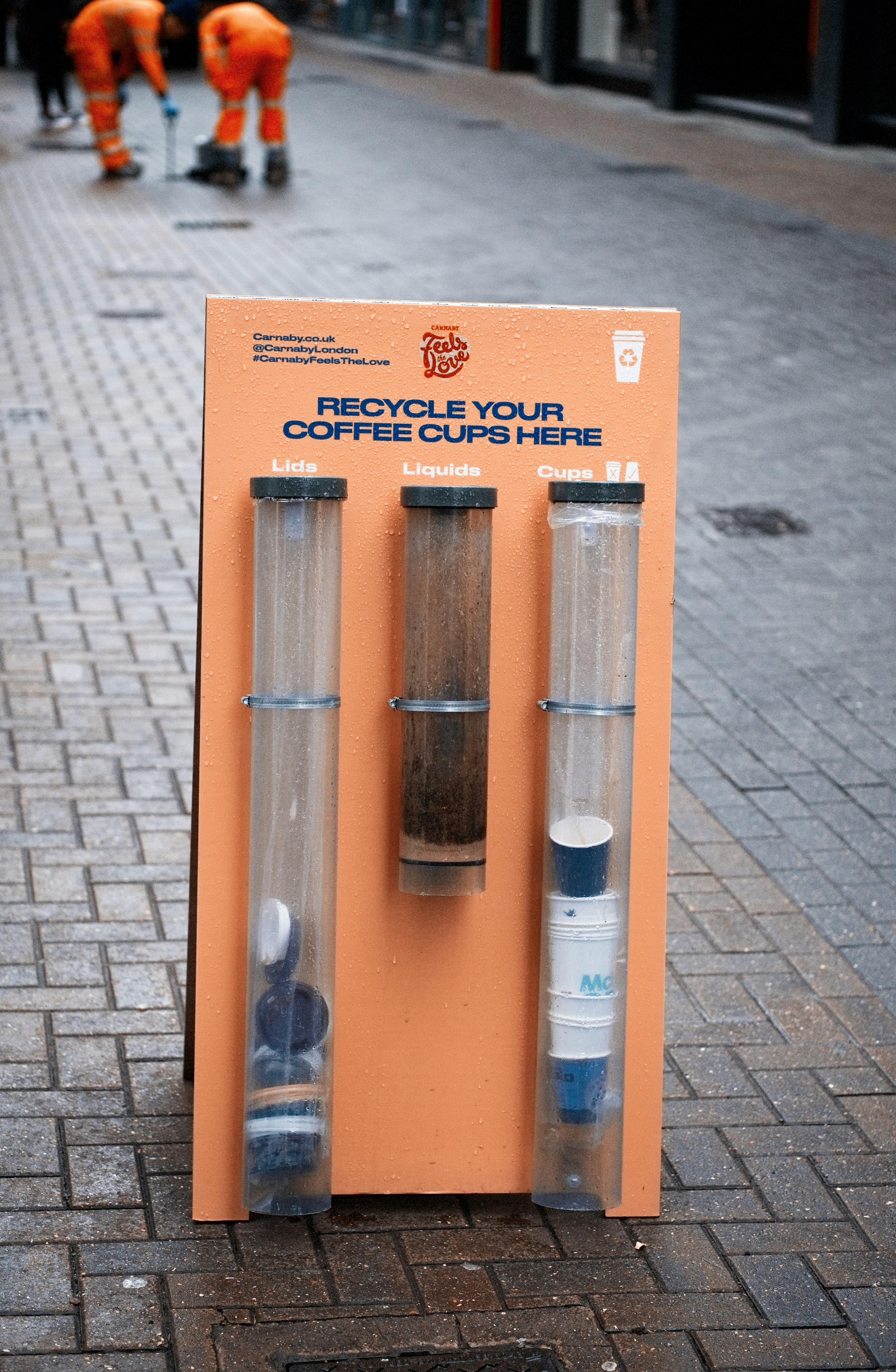 Stand Tall in Orange: A Coffee Cup Recycling Station on a Quiet Street