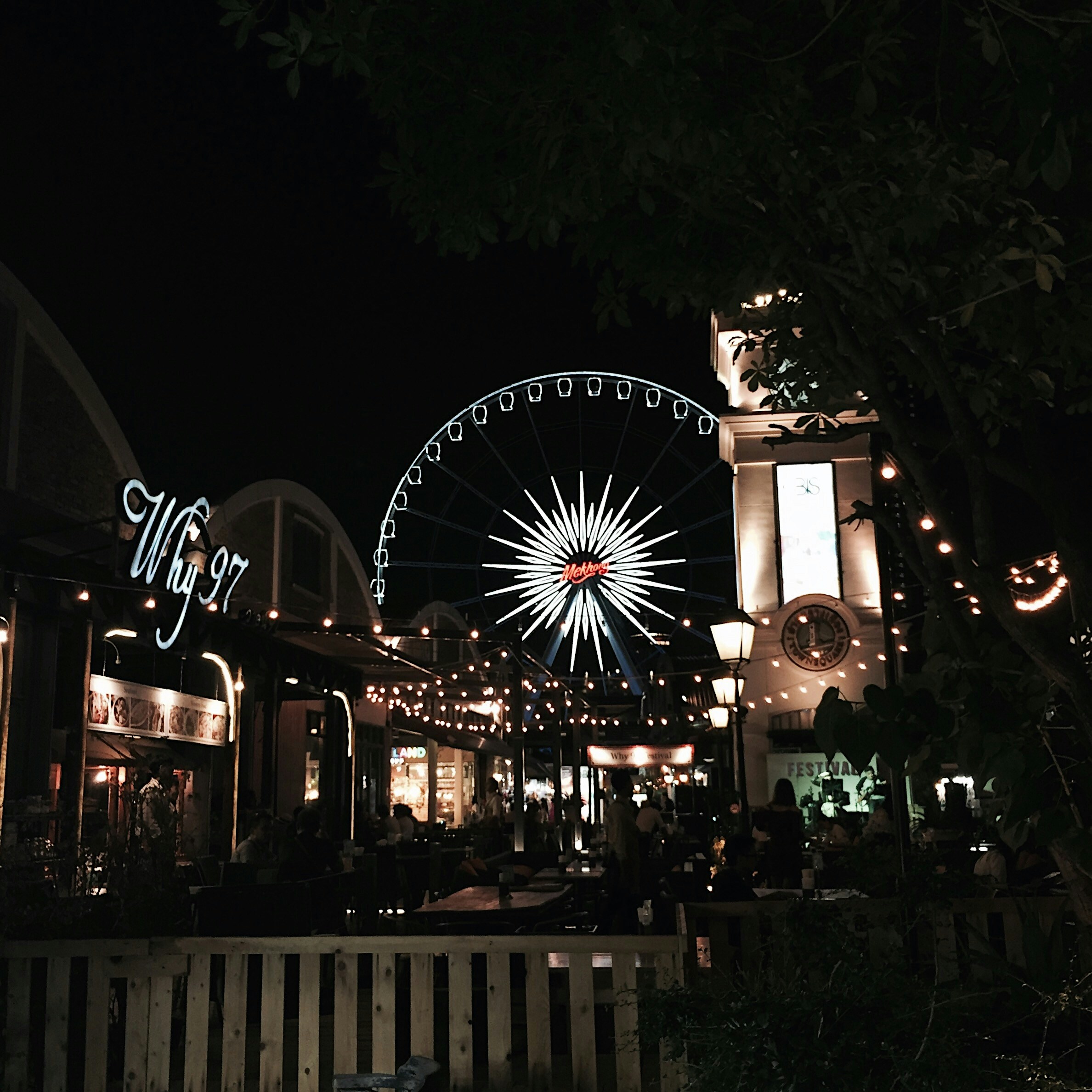 Neon Wheel of Night: A Ferris Glow Over the Courtyard