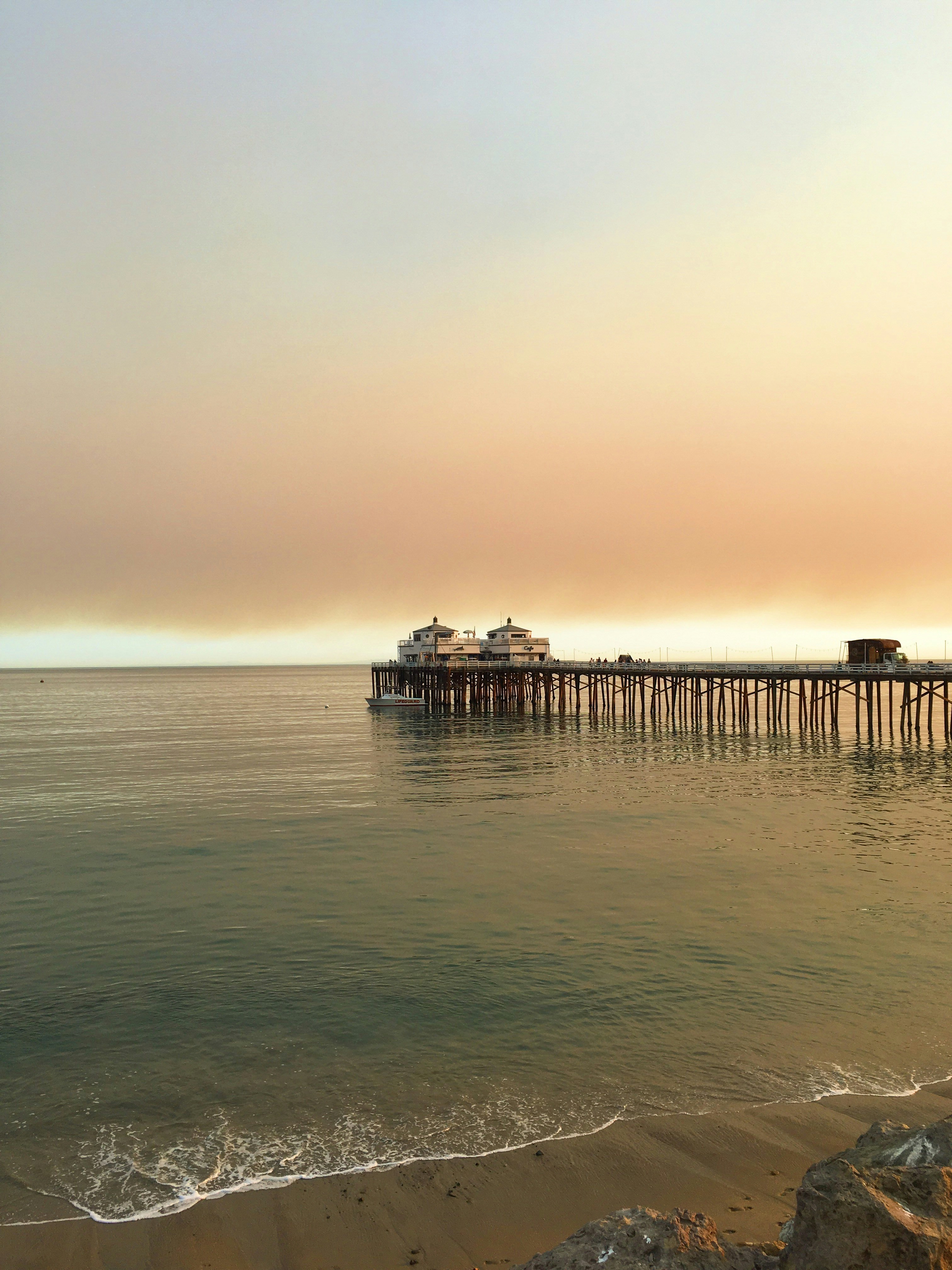 Pier extending into calm waters under a soft, pastel sky at dusk.