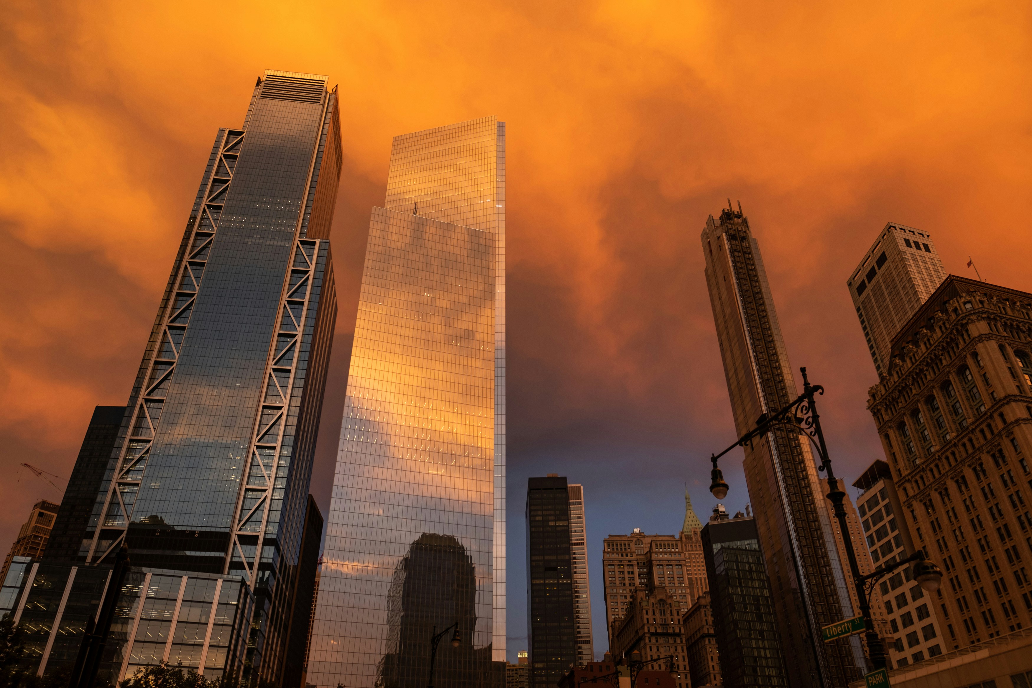 Skyscrapers reflecting vibrant orange clouds during sunset in New York City.
