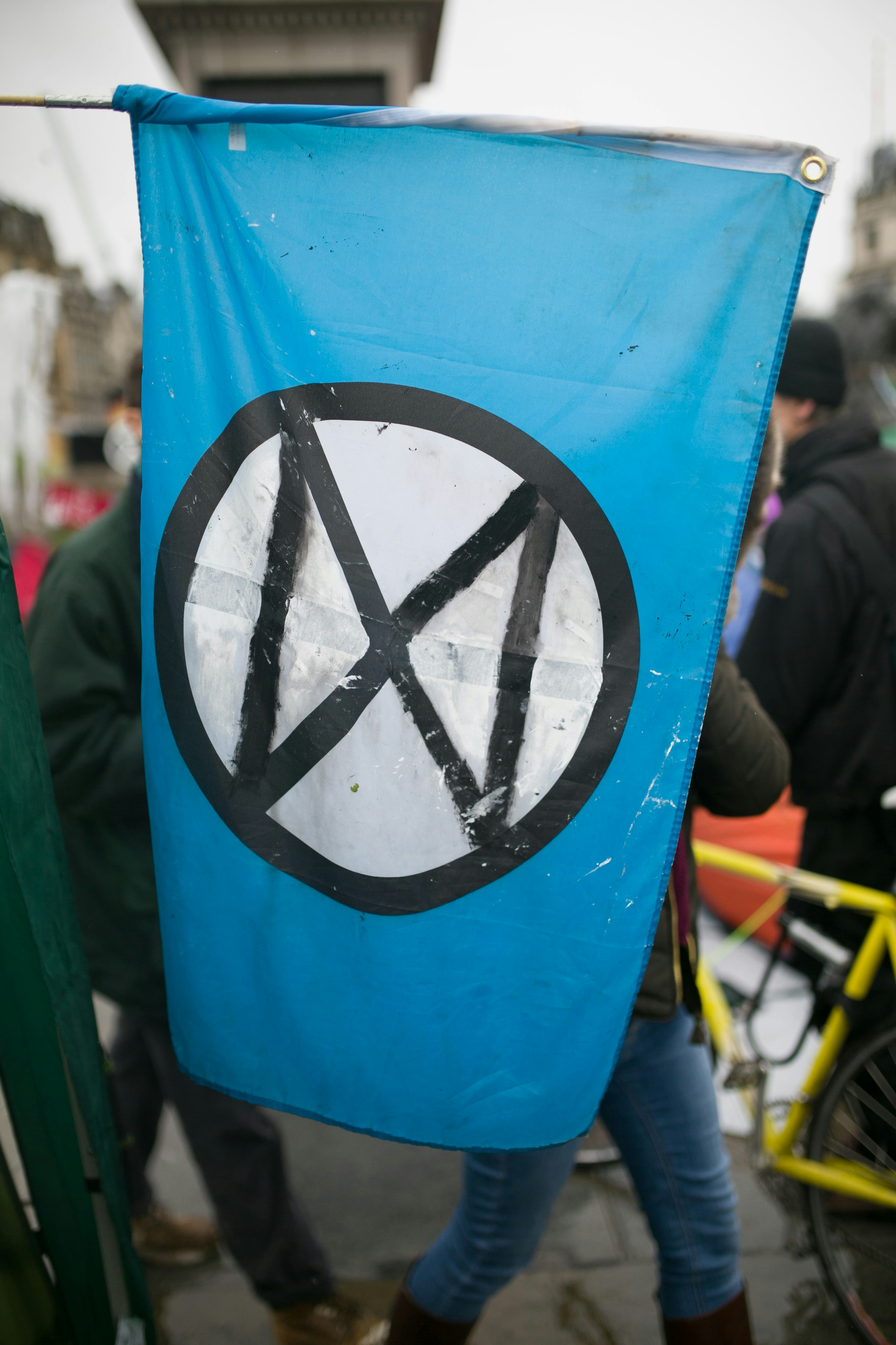 Blue banner bearing a bold black X inside a circle commands a city street scene