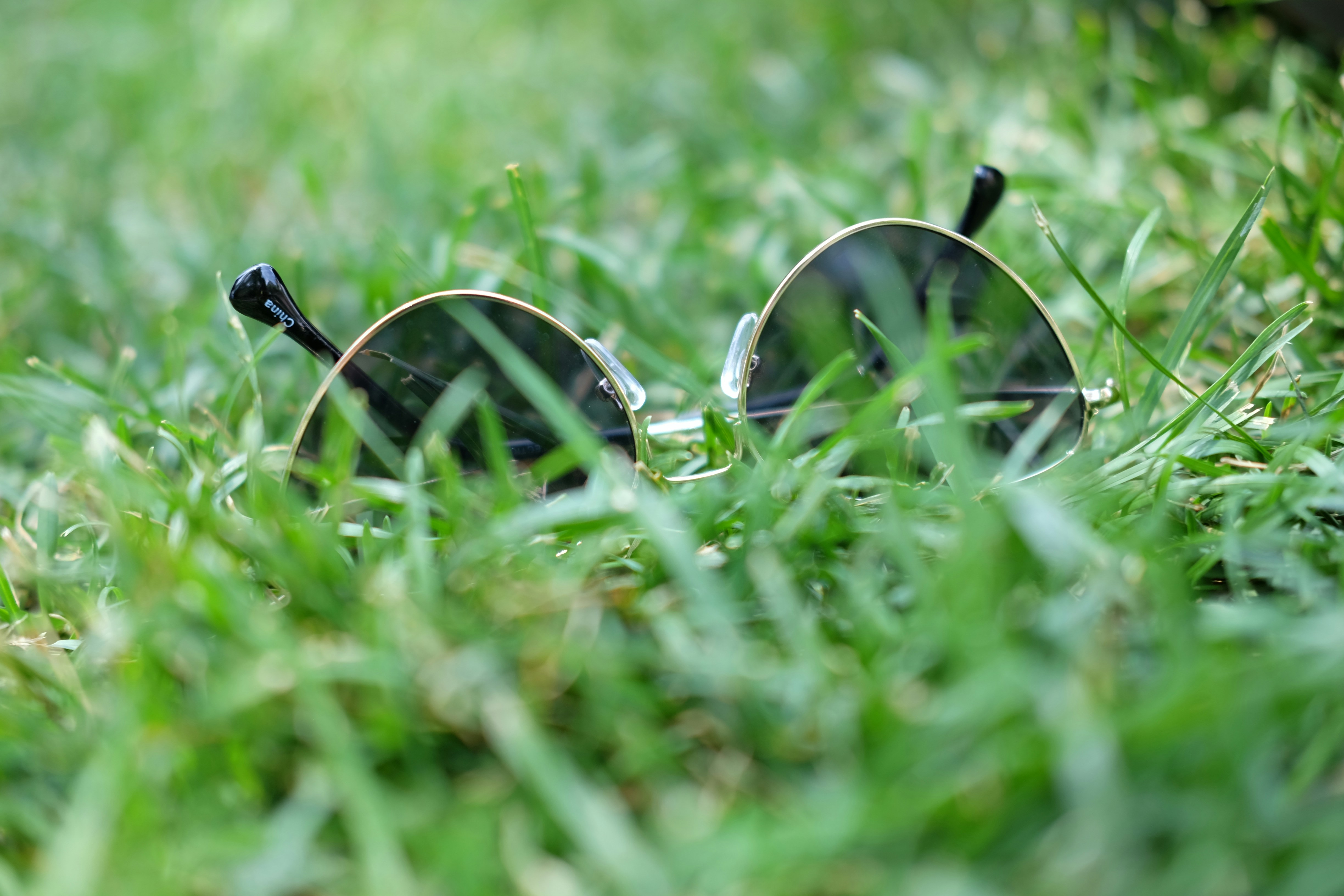 Round sunglasses nestled in lush green grass, capturing a laid-back summer vibe.