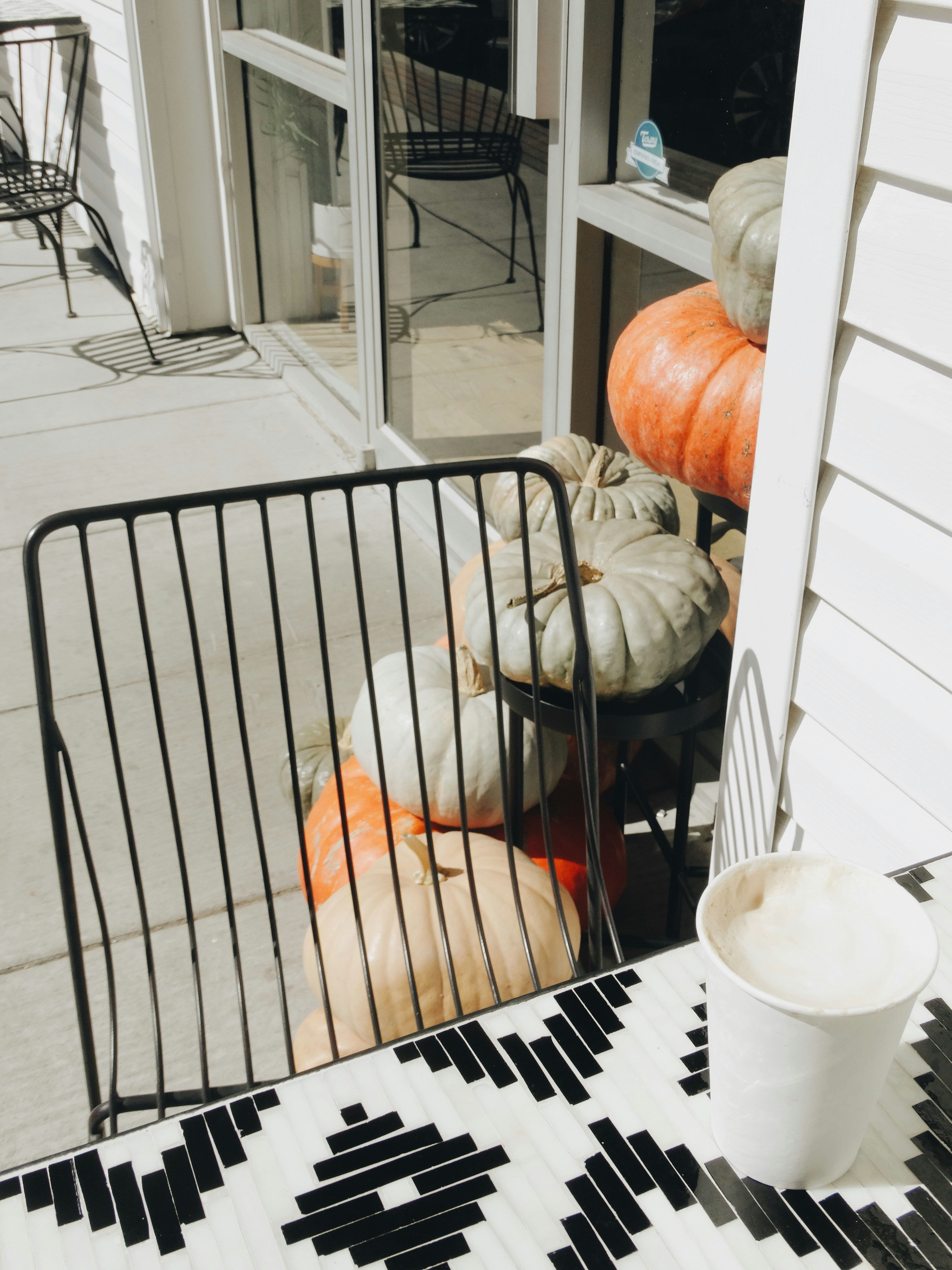 Pumpkins on a Café Chair: An Autumn Tableau by the Glass Doors