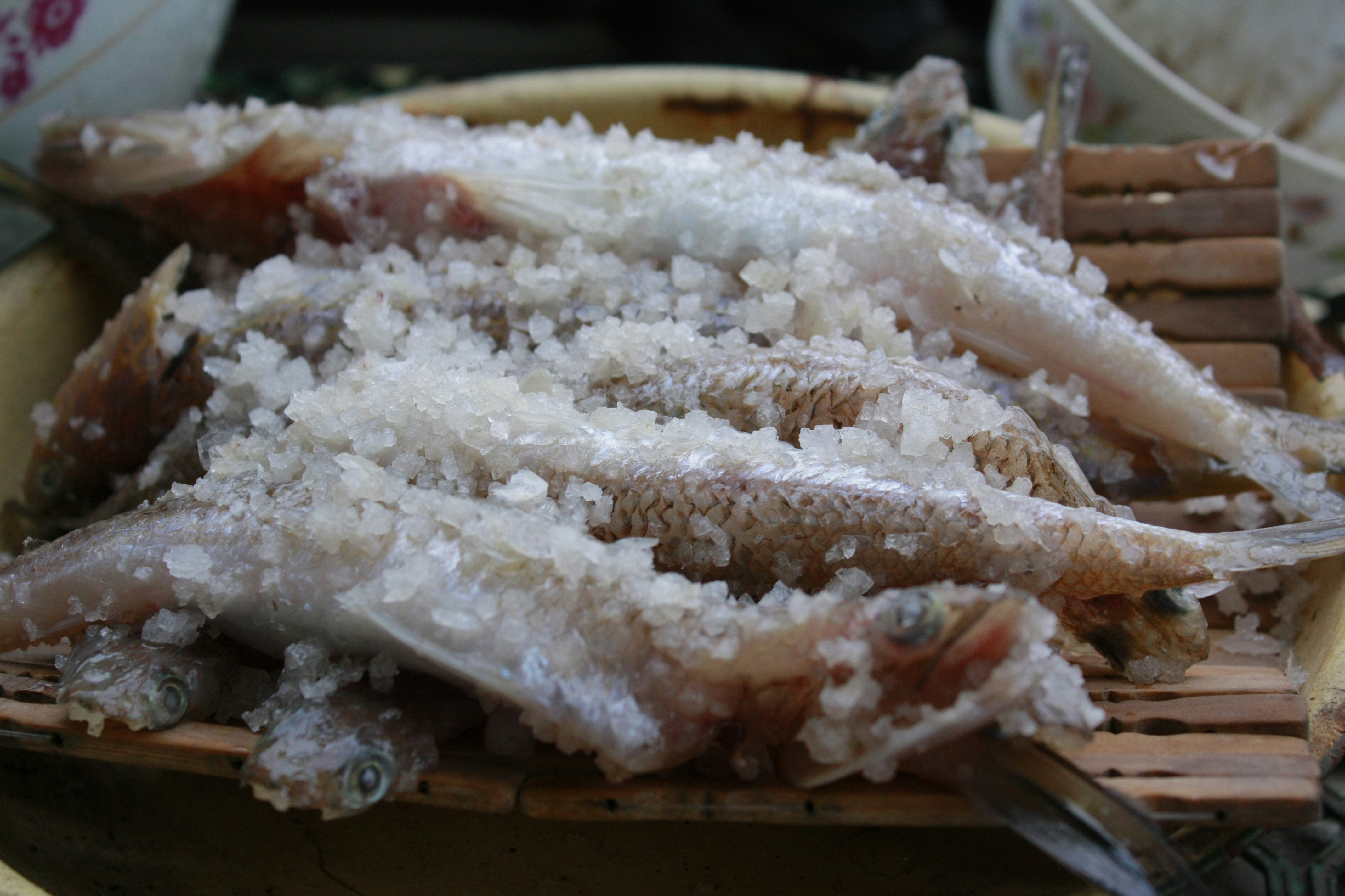 A platter of salt-cured fish arranged on a bamboo mat, highlighting traditional preservation methods.