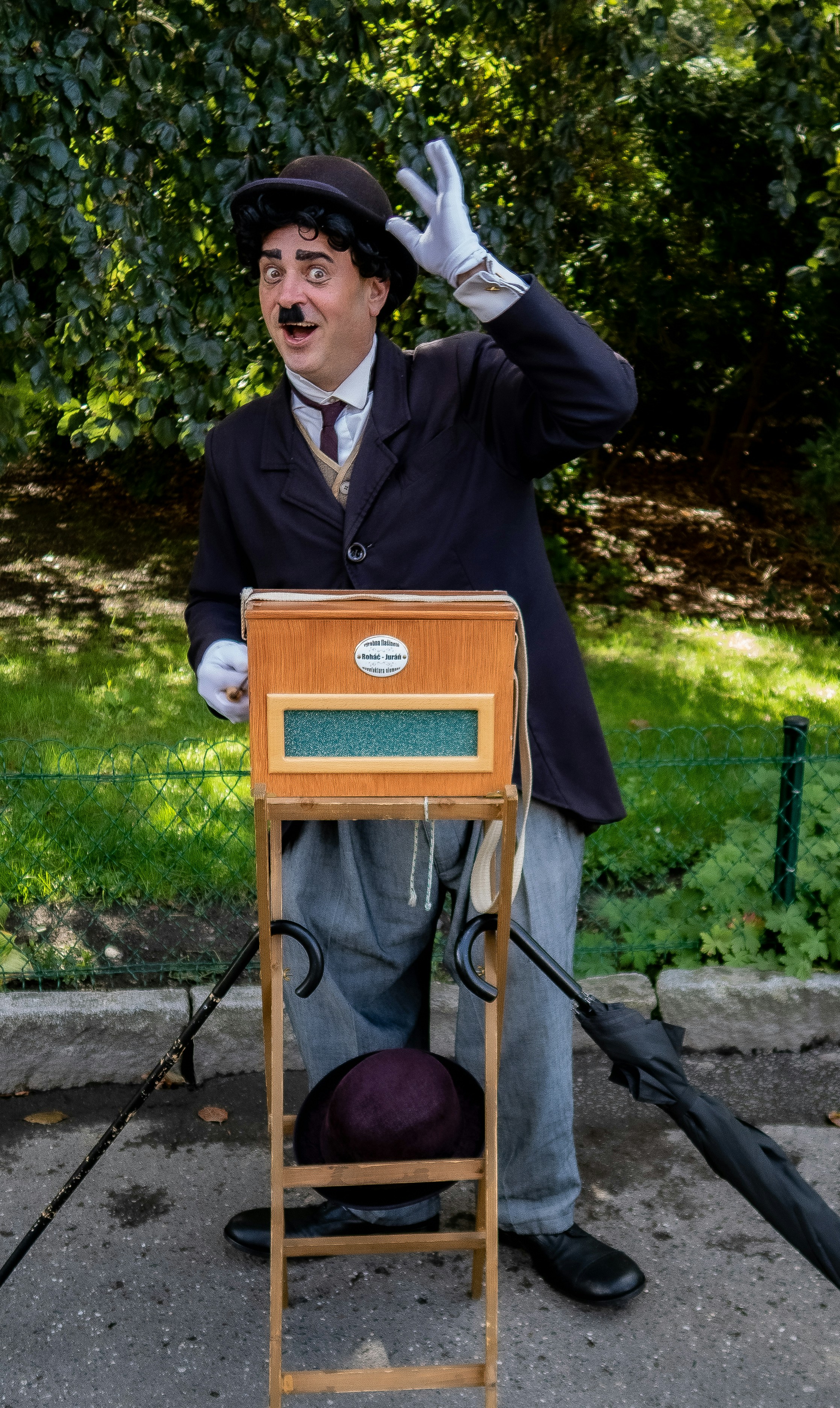 Man wearing Charlie Chaplin costume standing while waving his left hand ...