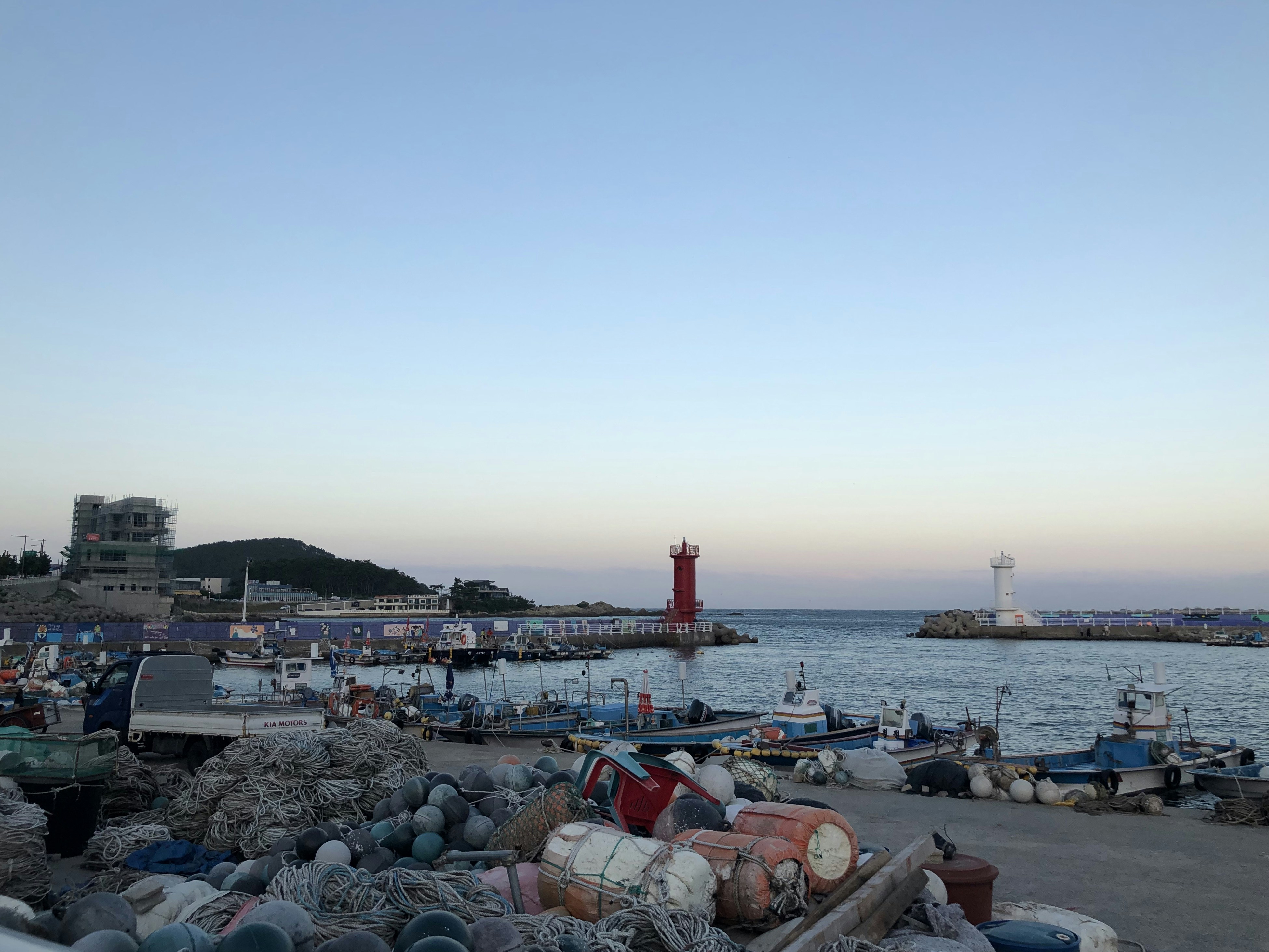 Crimson Beacon Over a Fleet-Strewn Seaside Harbor