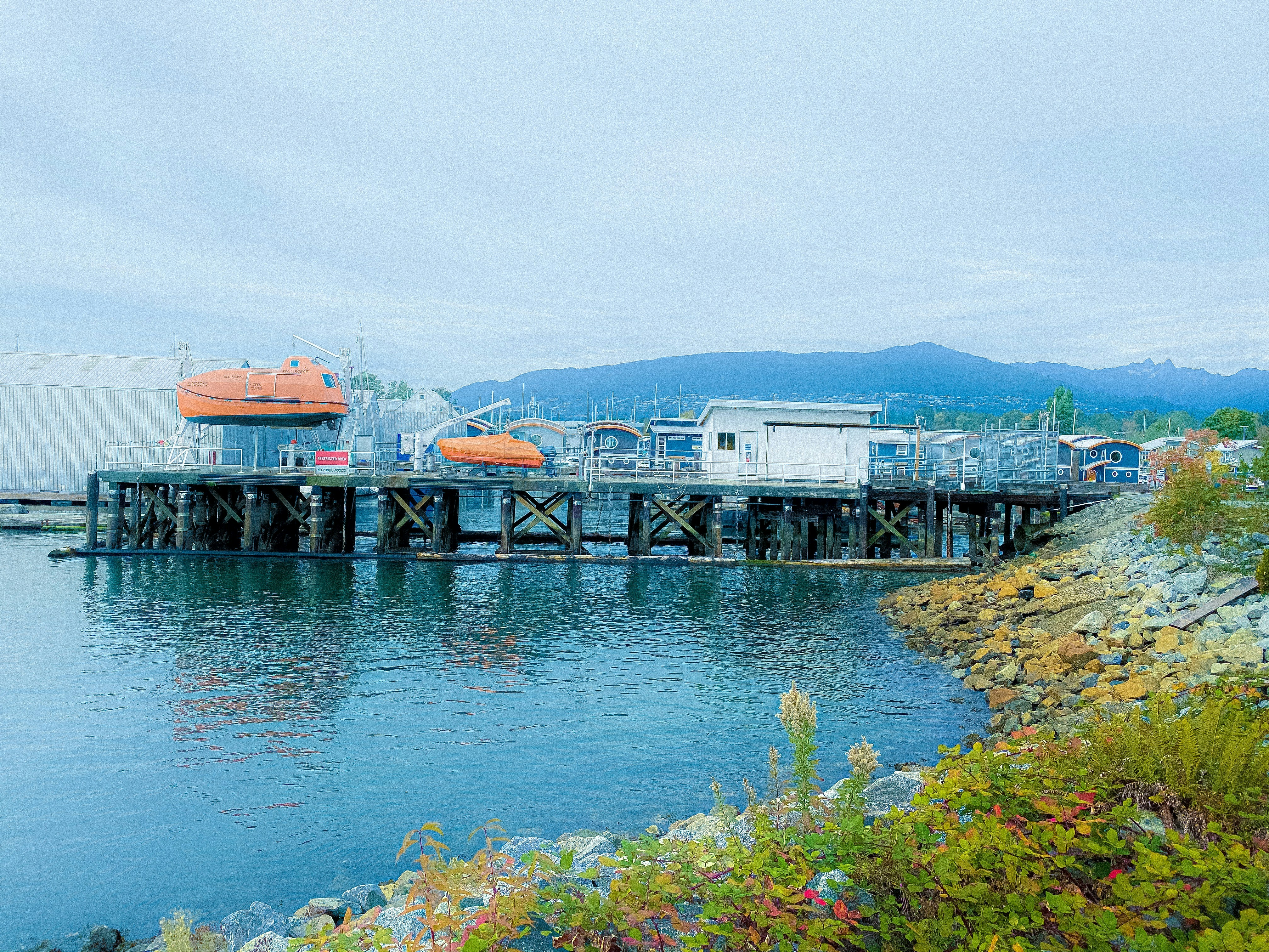 Orange Lifeboats Guard the Quiet Pier Over a Serene Bay