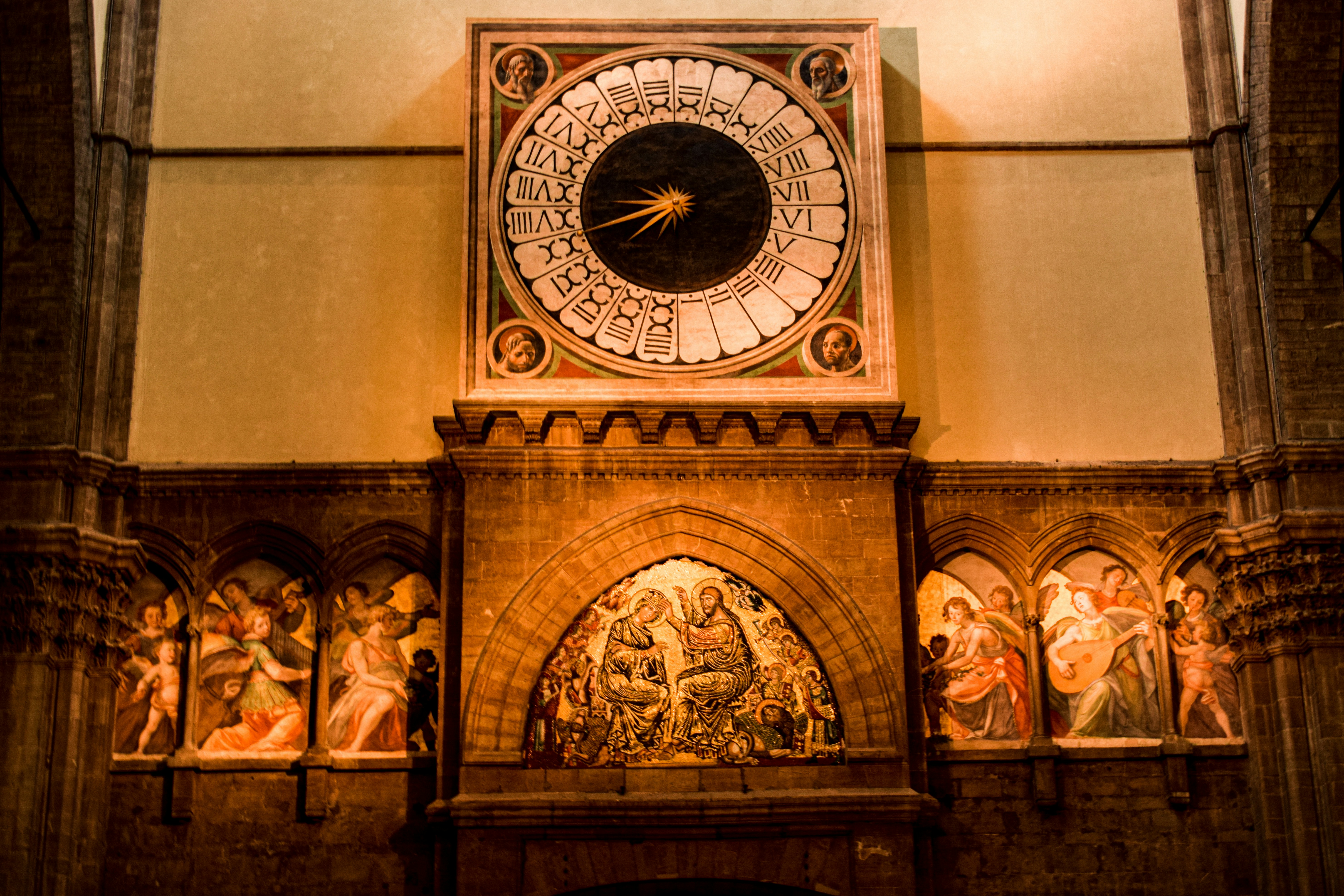 Ornate clock with intricate artwork set against a dimly lit, historic interior.