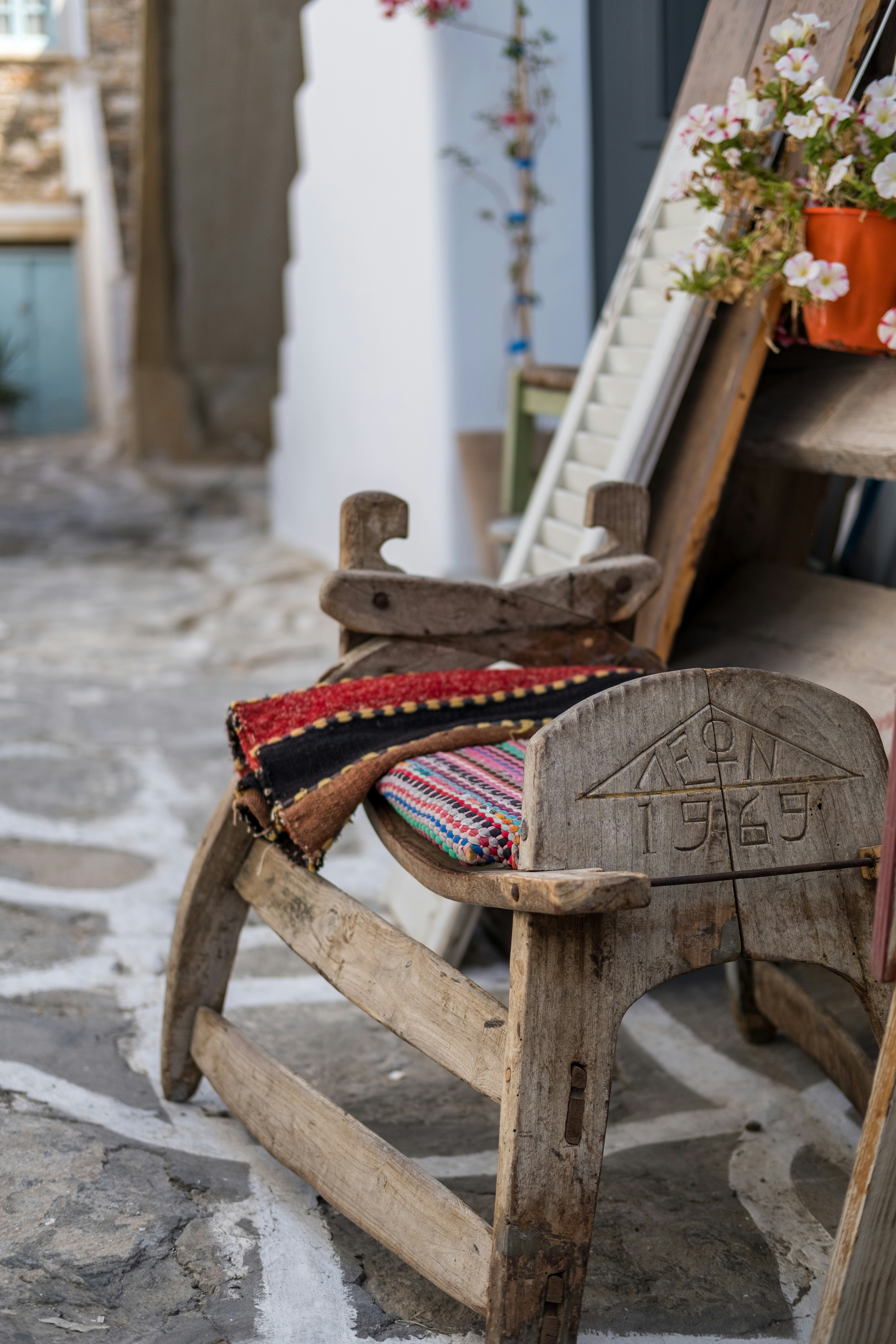Weathered wooden chair with woven cushions beside a sunlit market stall