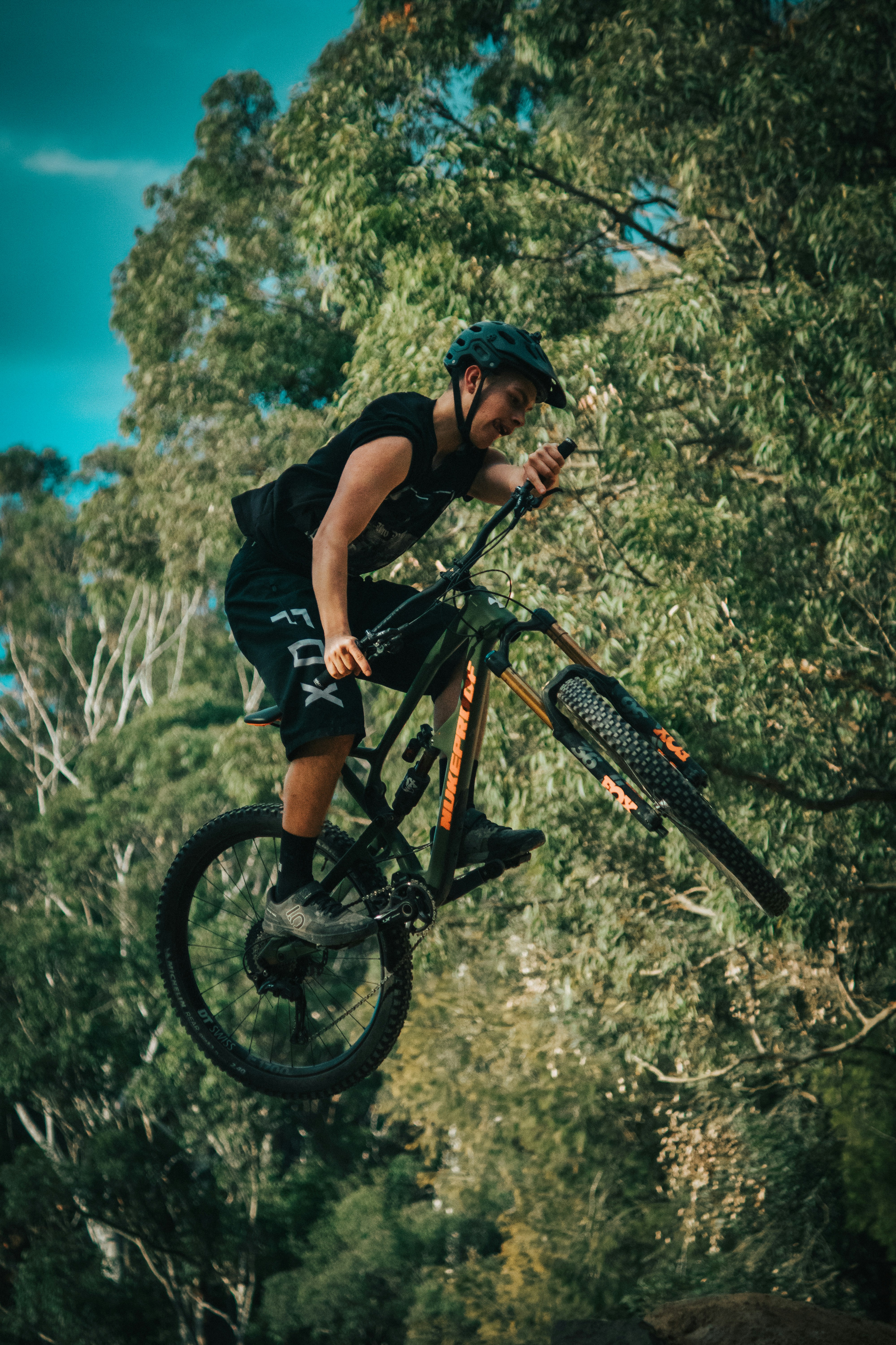 High-Flying MTB: Rider in Mid-Launch Against a Canopy of Green