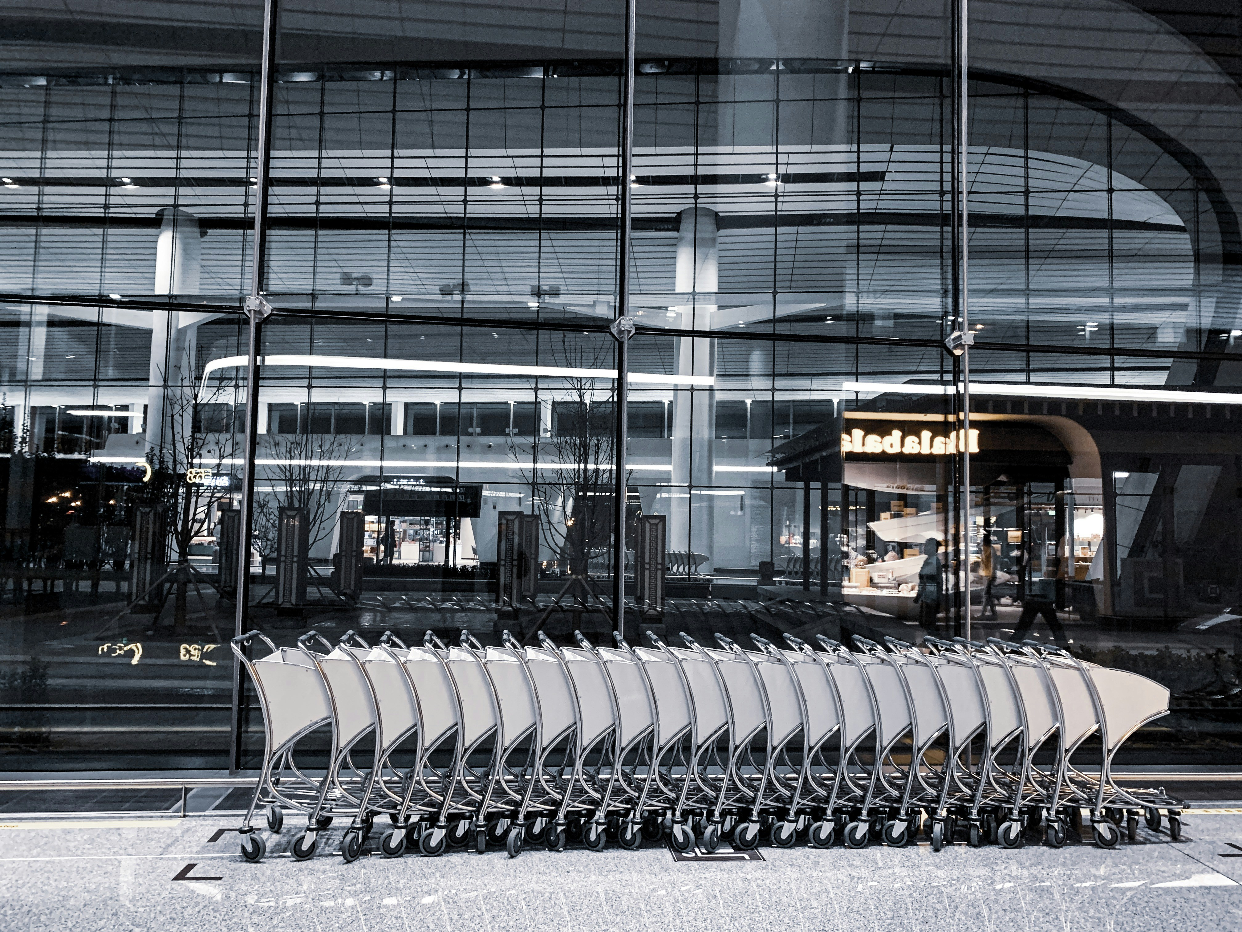 Stack of gray shopping carts by glass walled building photo – Free Grey ...