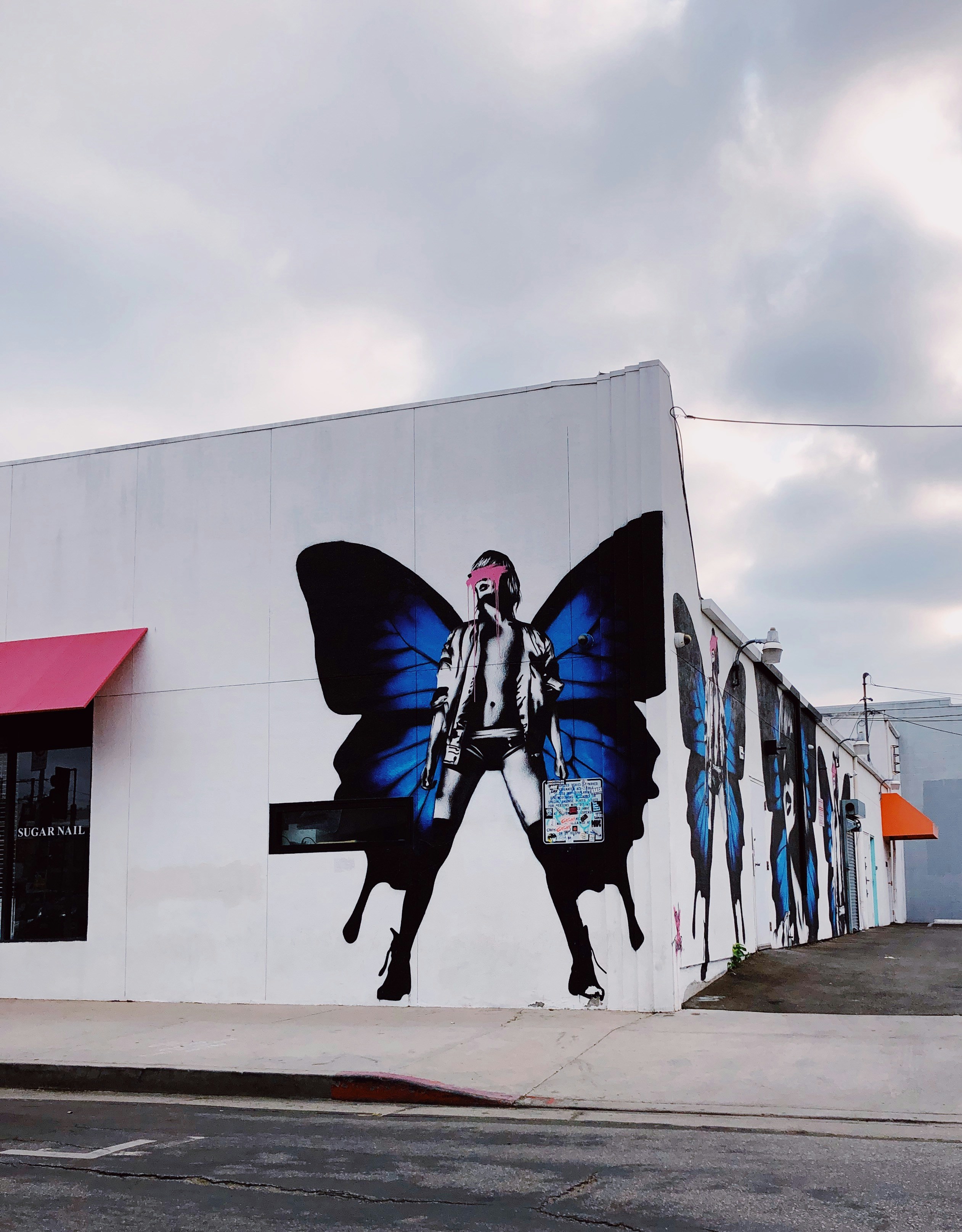 Blue-Winged Figure on a White Wall: A Street-Art Moment