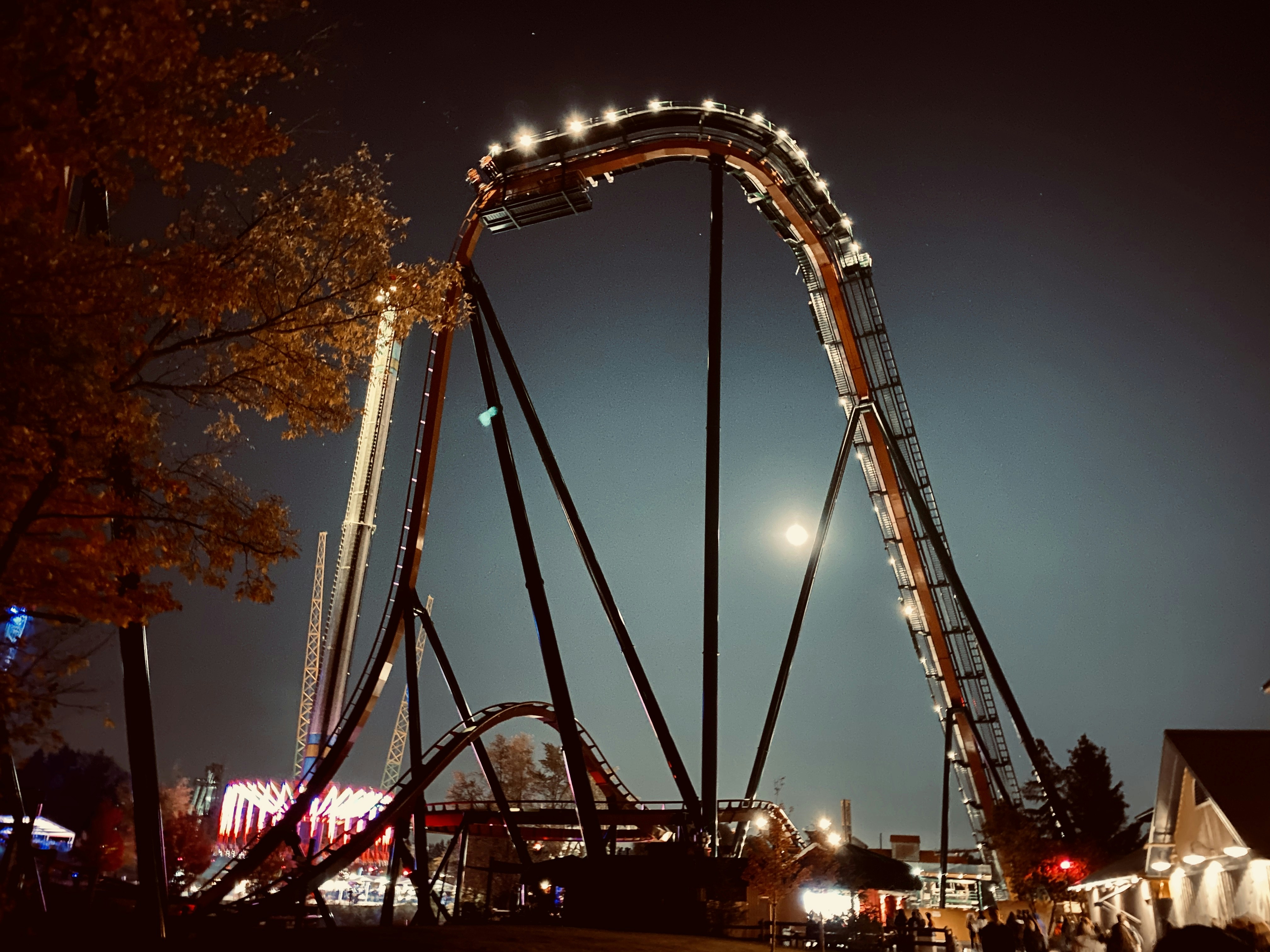 A roller coaster at night with a full moon in the background photo ...