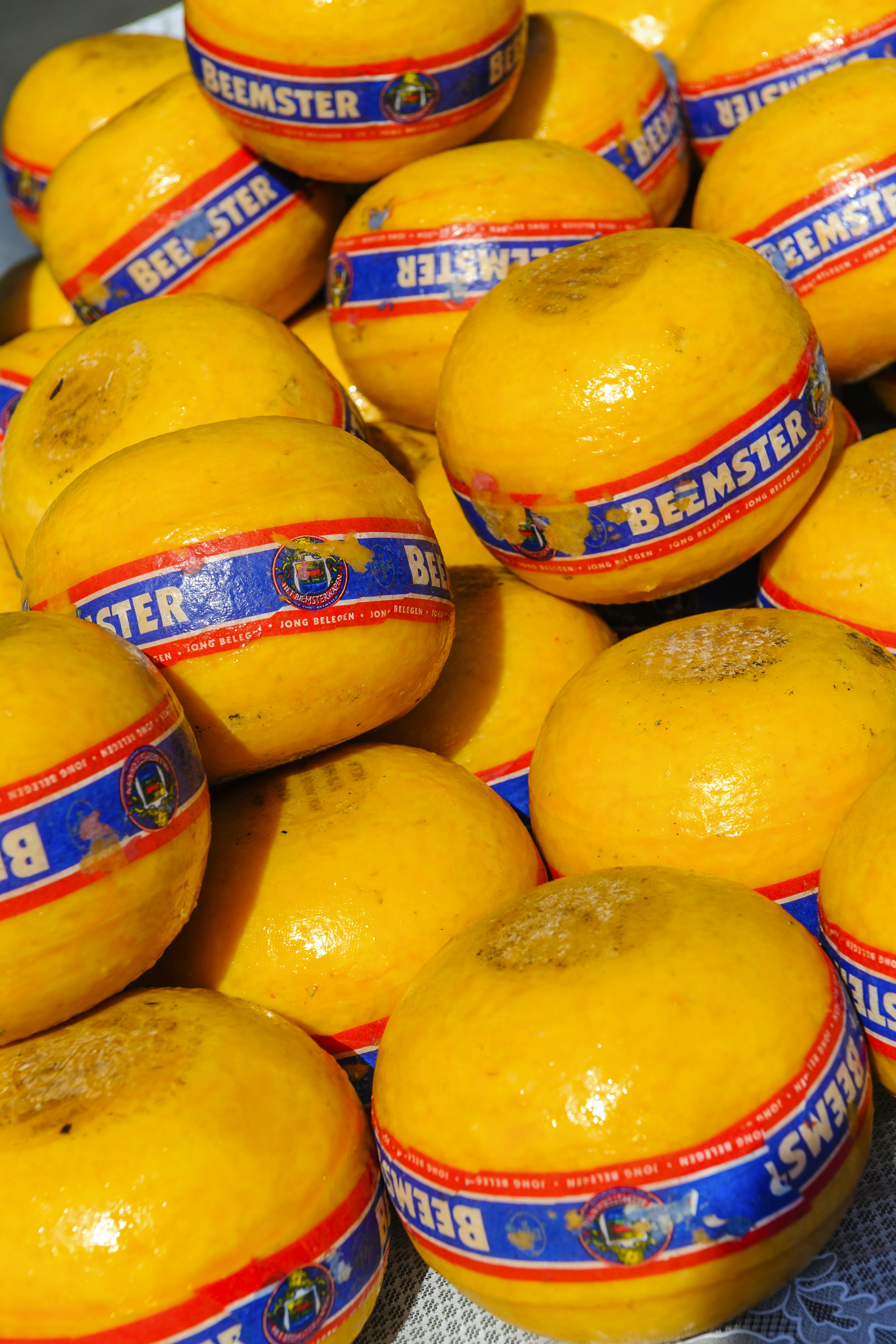 Stacks of bright yellow Beemster cheese wheels with vibrant labels.