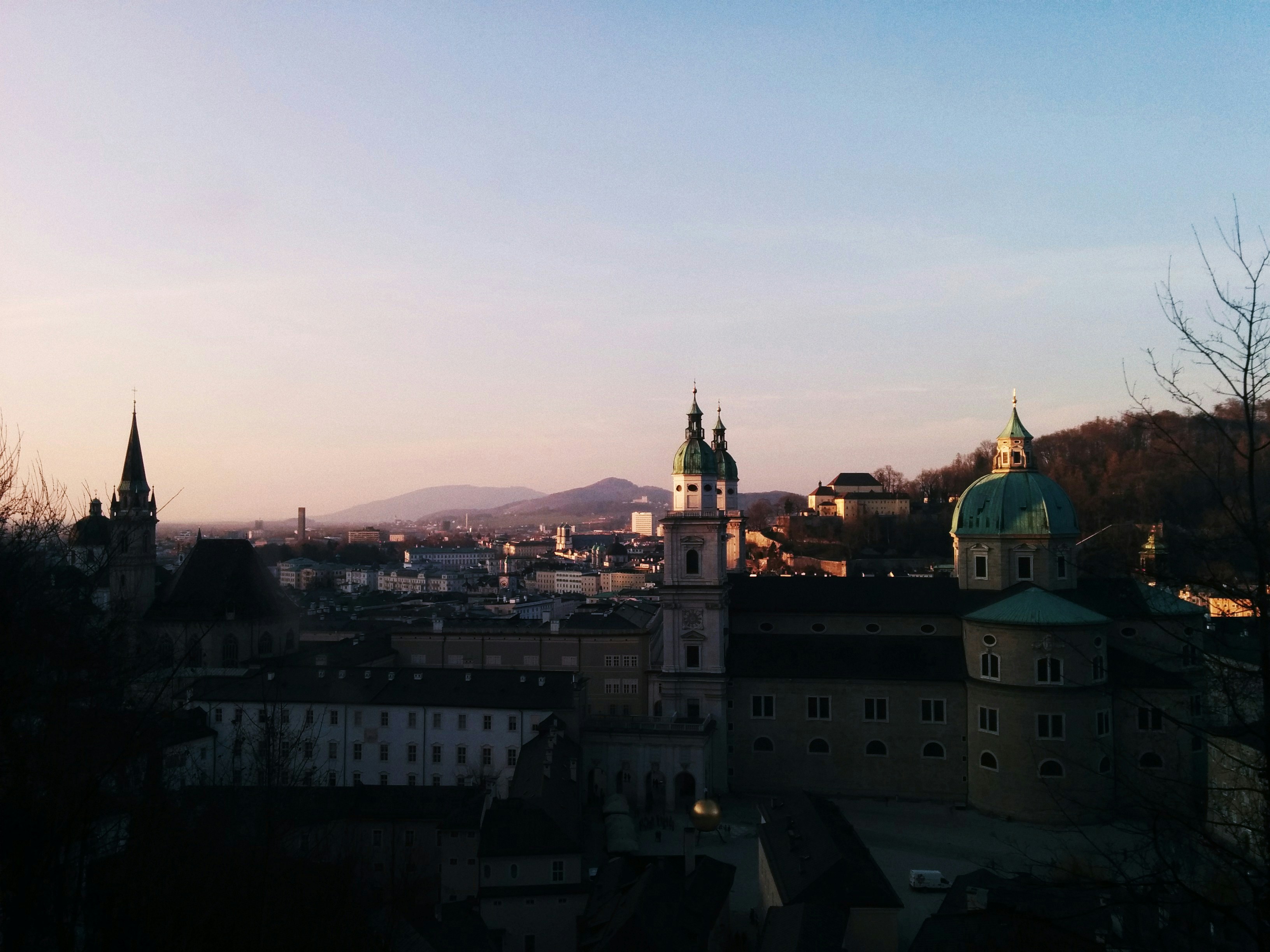 Silhouetted cityscape with church towers under a dusky sky.