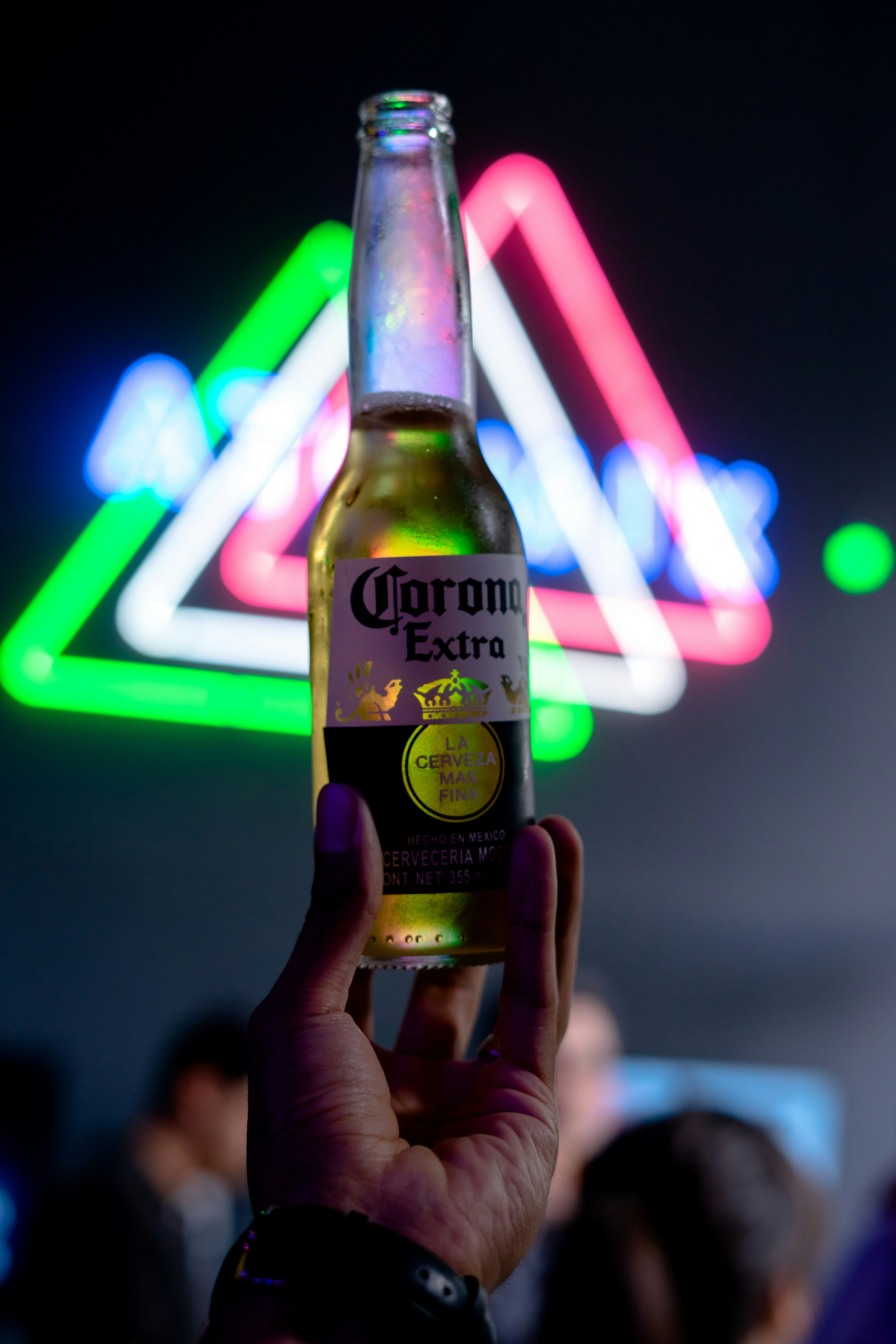 Neon Triangles Framing a Corona Bottle: A Nightlife Toast