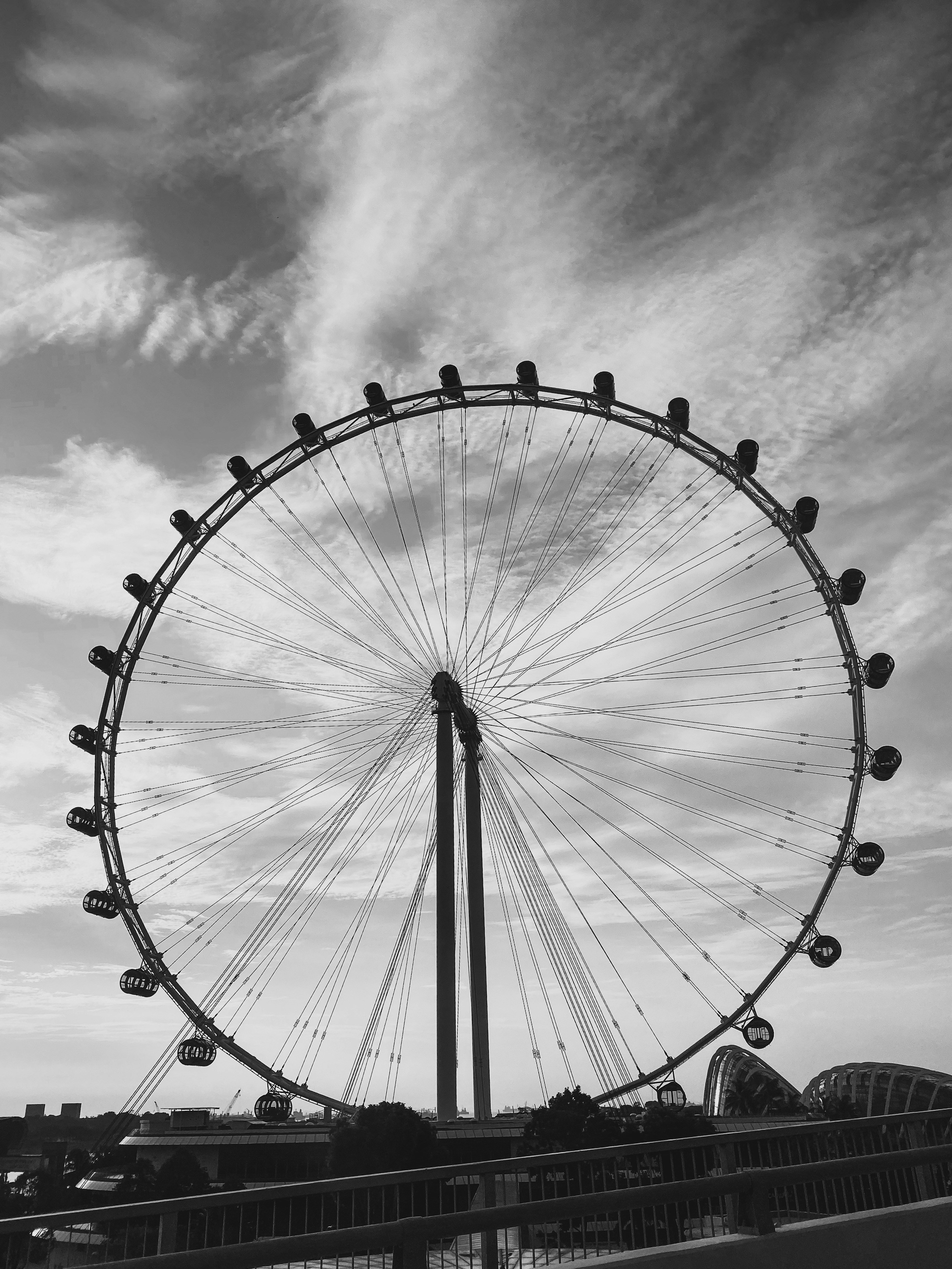 Spoked Horizon: A grayscale portrait of the Ferris wheel beneath drifting clouds