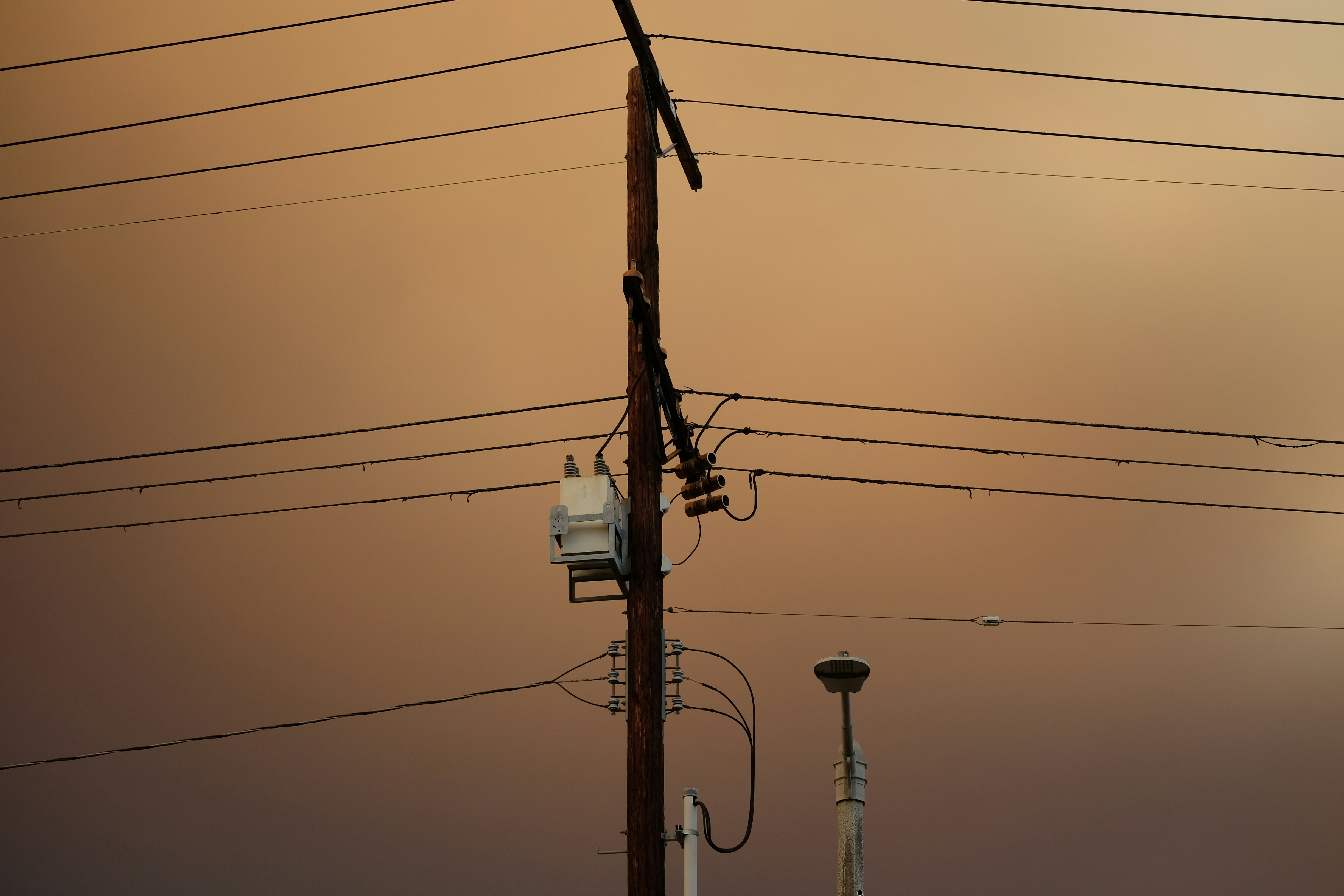 Poleline at Dusk: Quiet Geometry of Wires against an Orange Sky