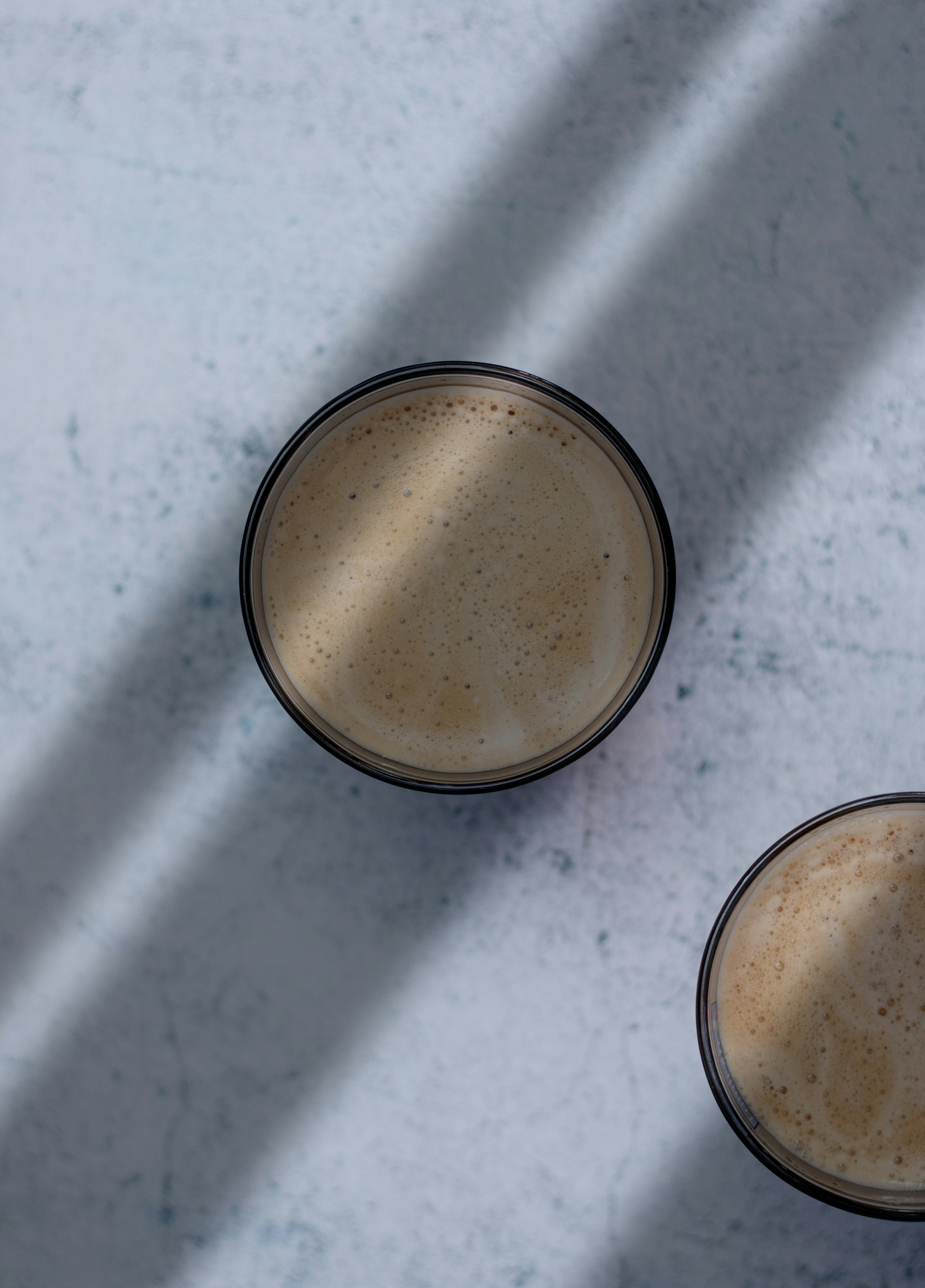 Top-Down Morning: Two Coffee Cups under a Diagonal Shadow on Marble