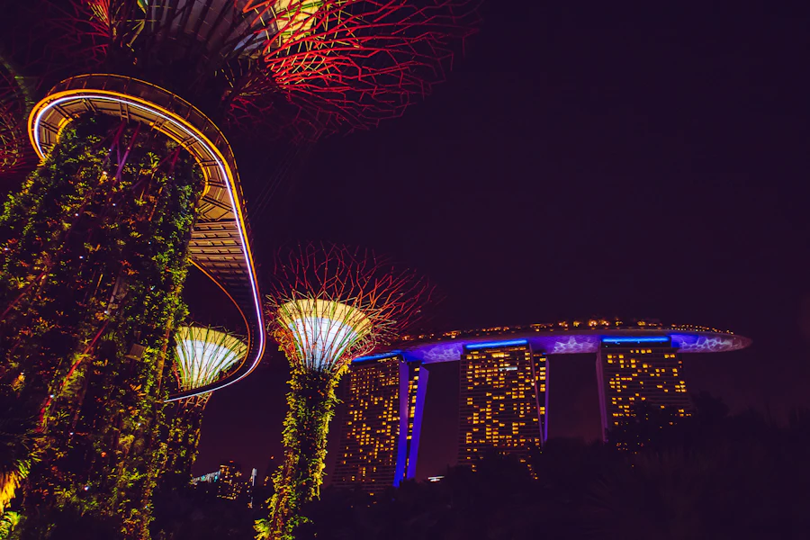 Illuminated Supertree structures and the Marina Bay Sands skyline glowing against a dark night sky. Neon purple, blue, and gold lights dominate the scene.