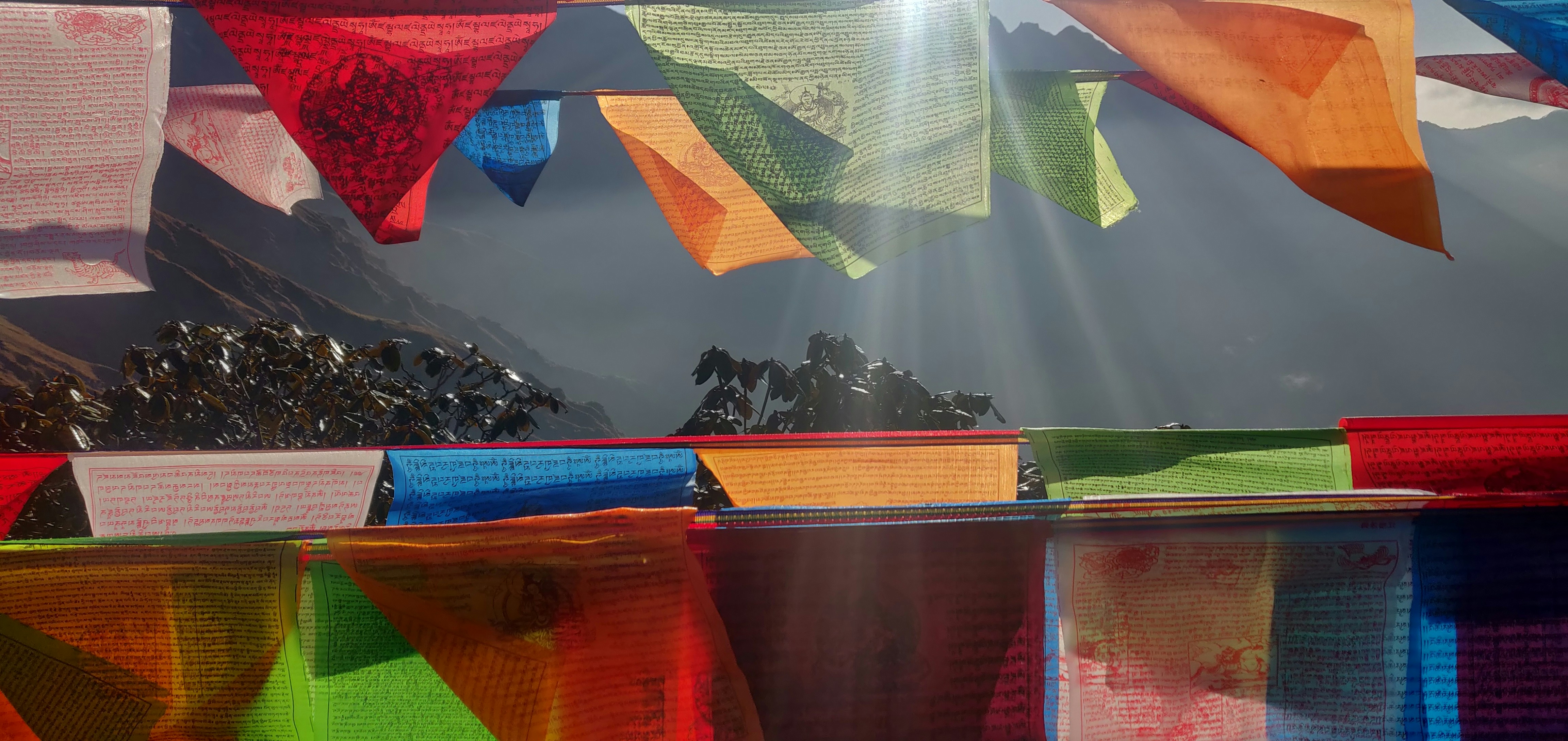 Sunlit Prayer Flags: Windswept Colors Above Snowy Peaks