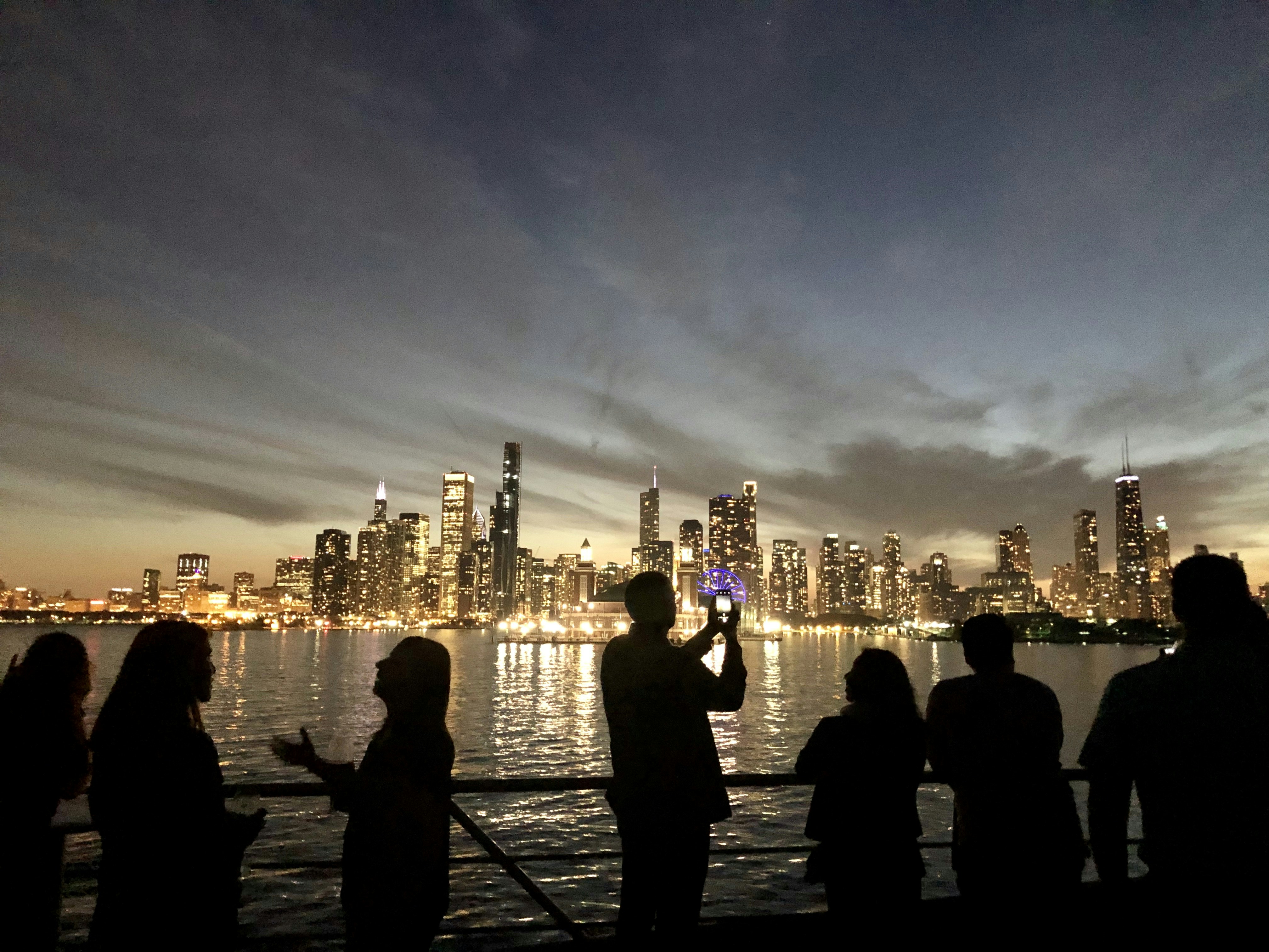 Silhouettes at Dusk: City Lights Beyond the River