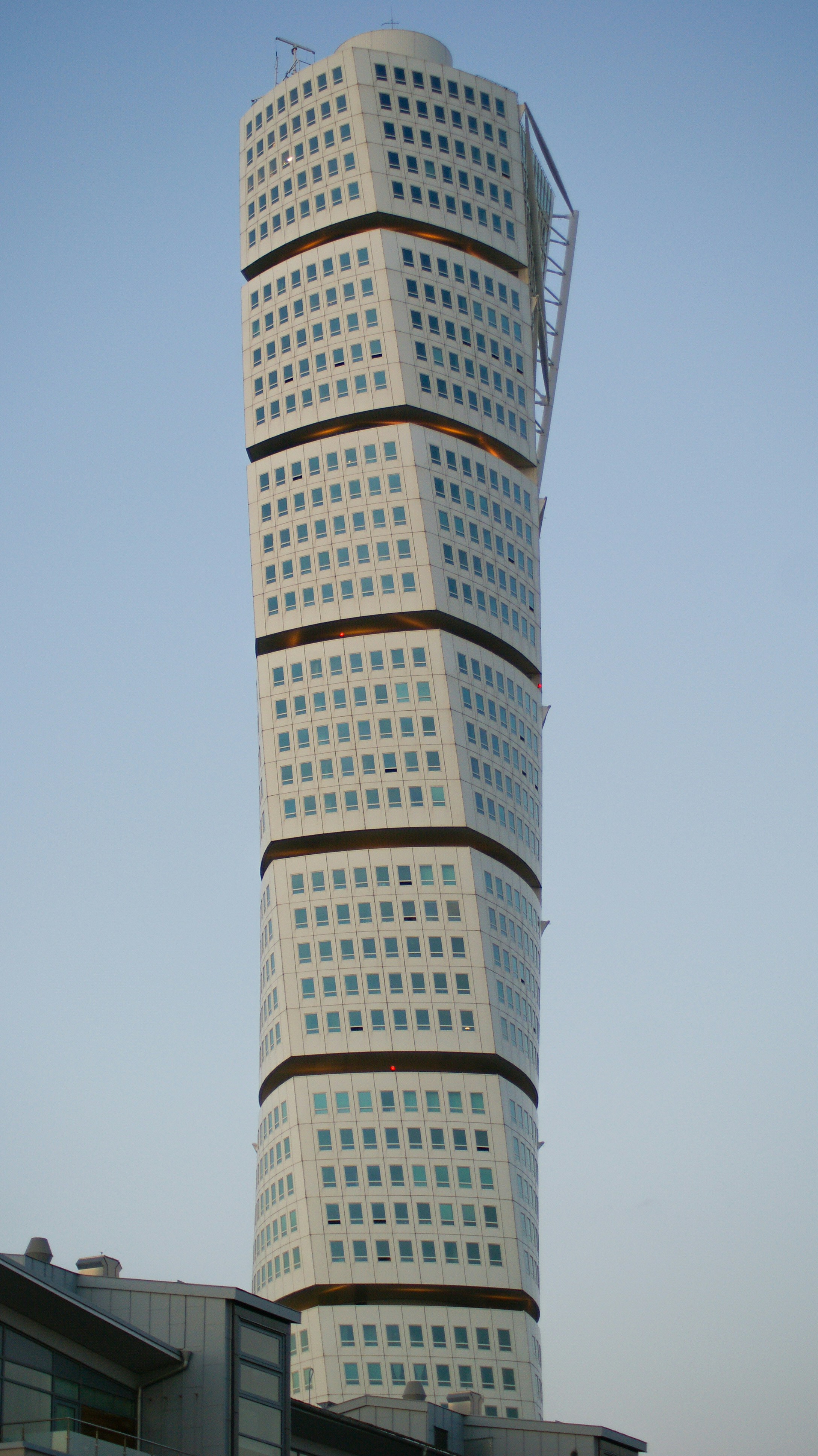 A uniquely designed skyscraper with a twisting structure, showcasing modern architecture against a clear sky.