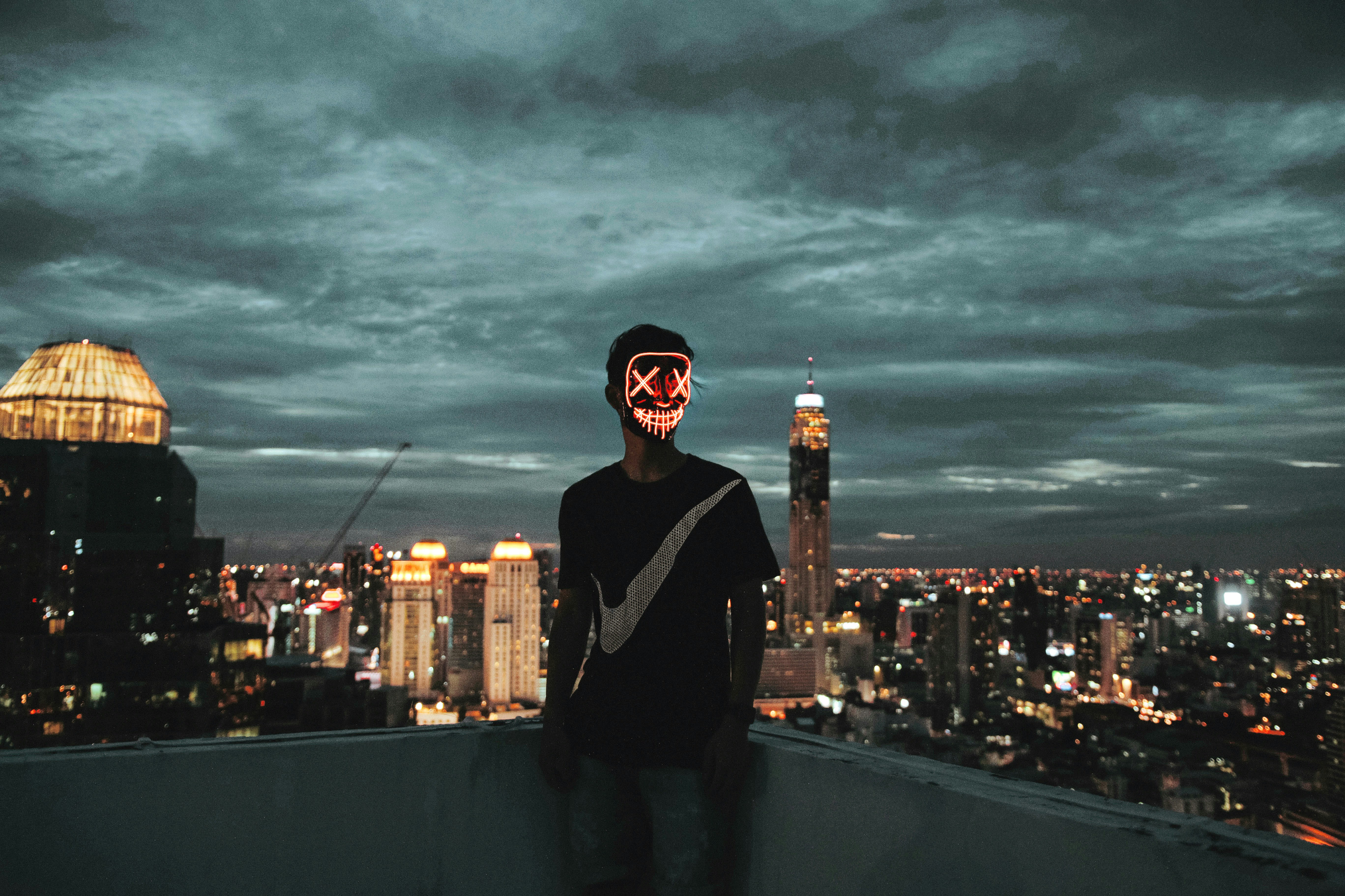 Silhouette of a person standing on a rooftop against a vibrant cityscape at dusk.