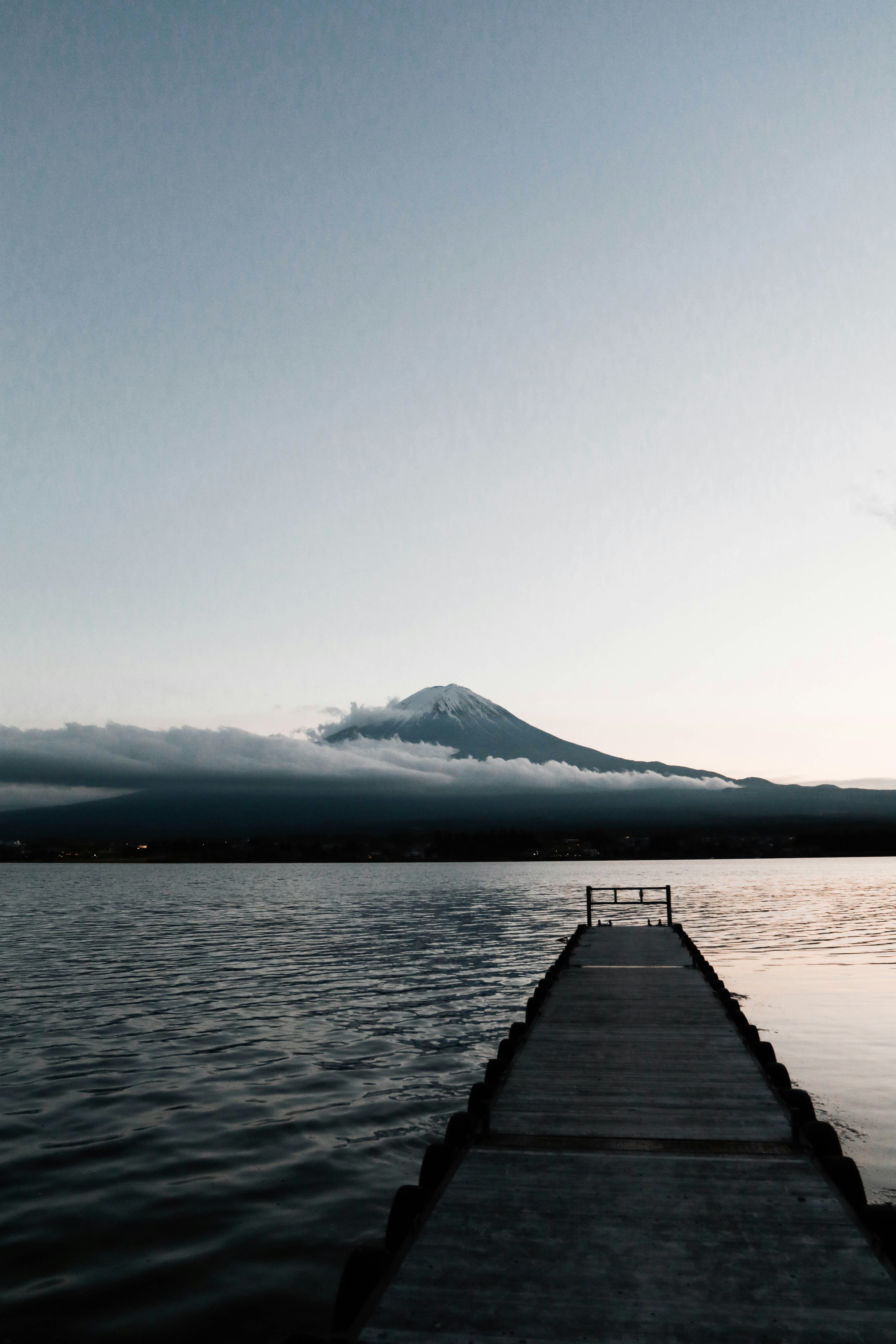Gray wooden beach dock viewing body of water and mountain during ...