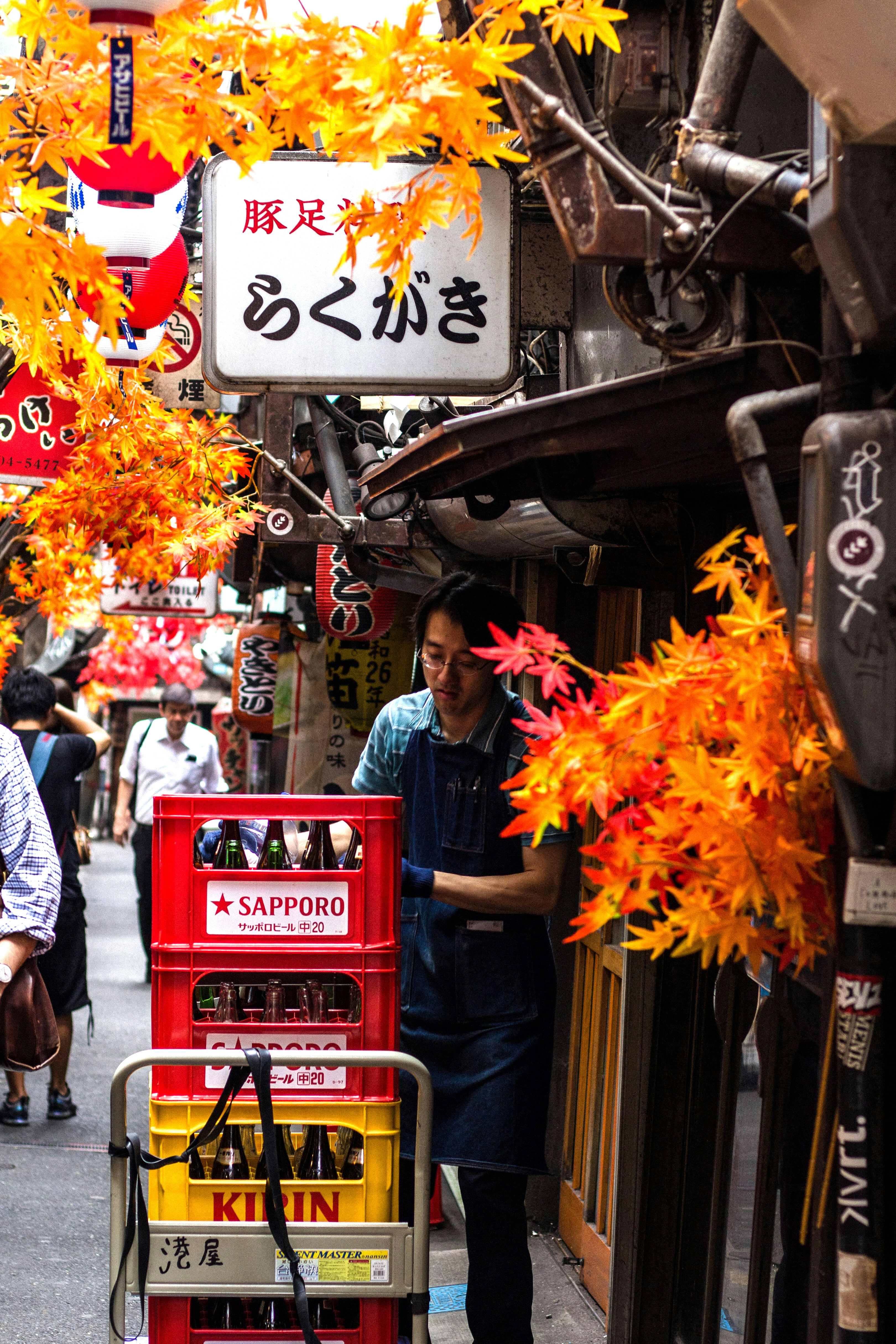 Autumn Neon in a Narrow Japanese Alleyway: Crates, Signage, and a Street Vendor